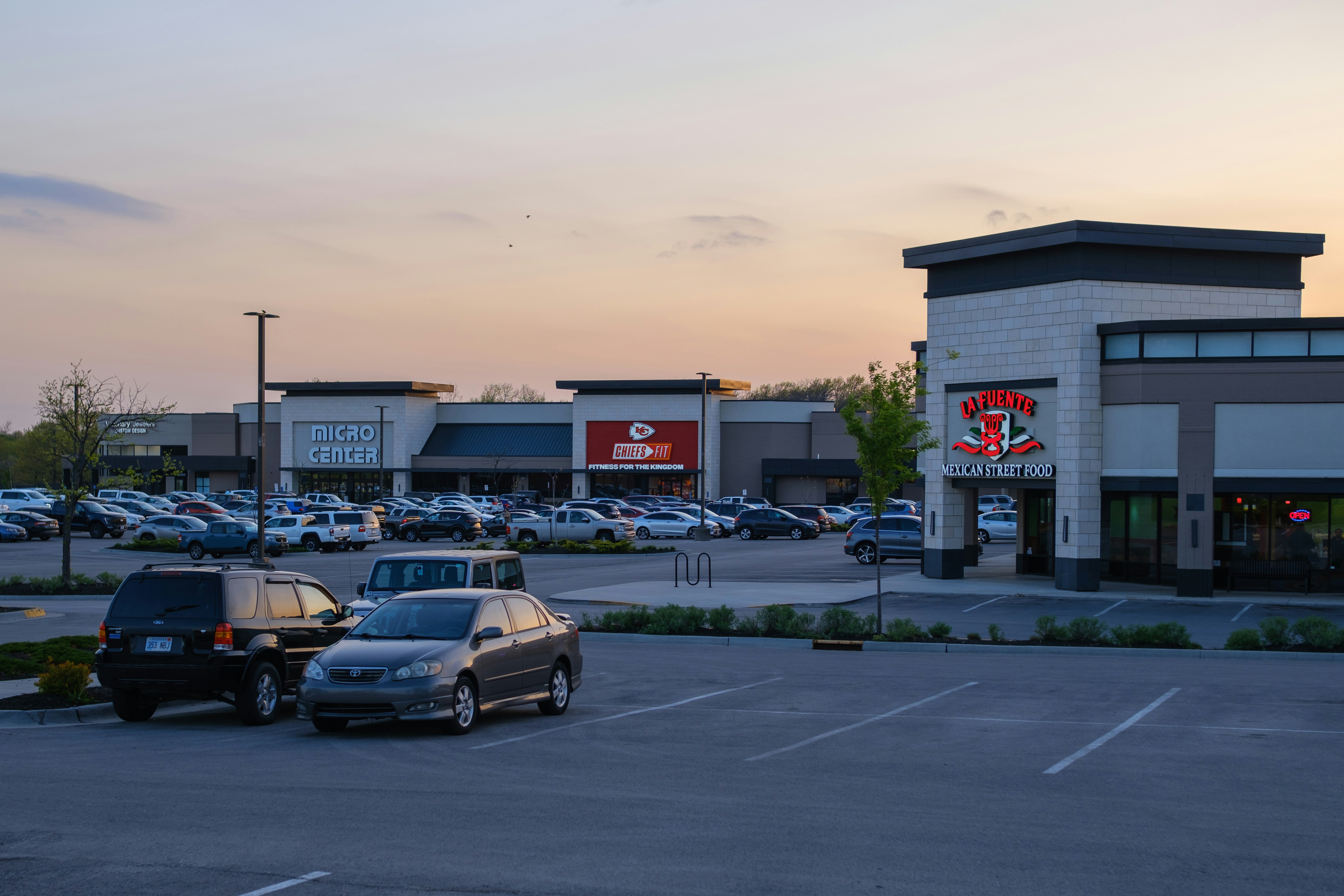 Neon Sign and Strip Mall Amid a Quiet Parking Lot at Dusk