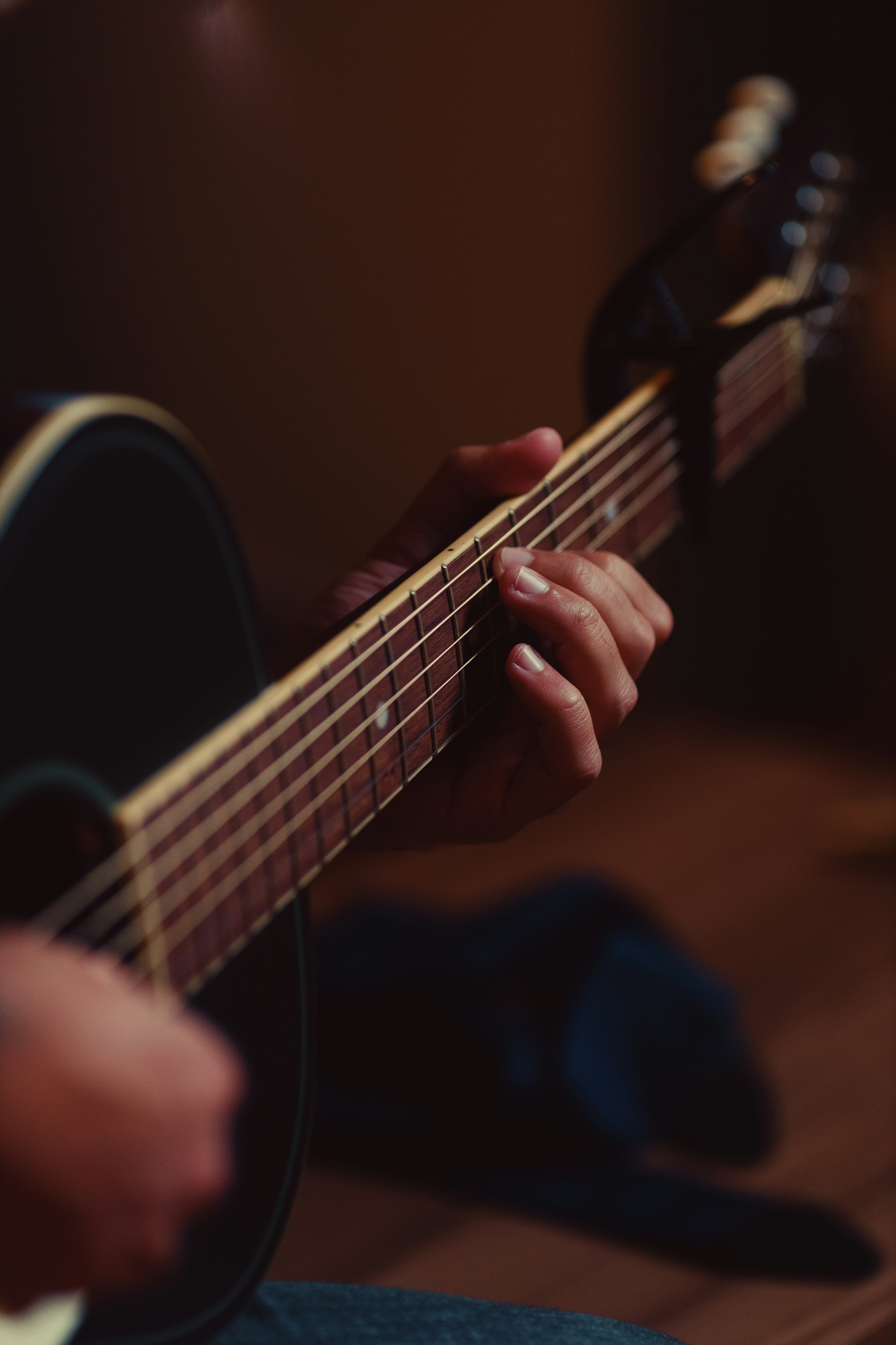 Focused Fingertips: A Guitarist’s Moment in Warm Dim Light