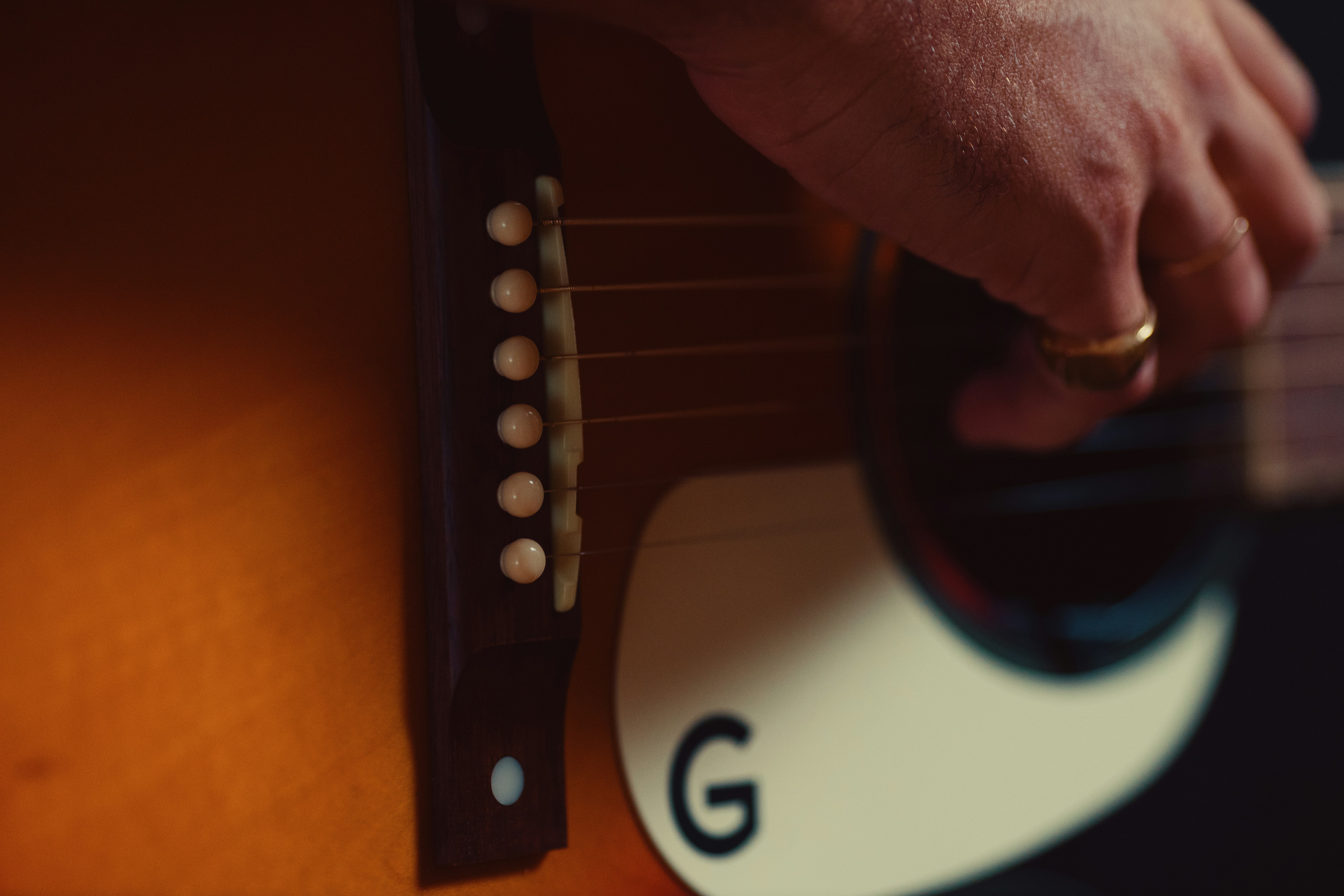 Strings of Focus: A Guitar's Edge and Hands in Soft Light