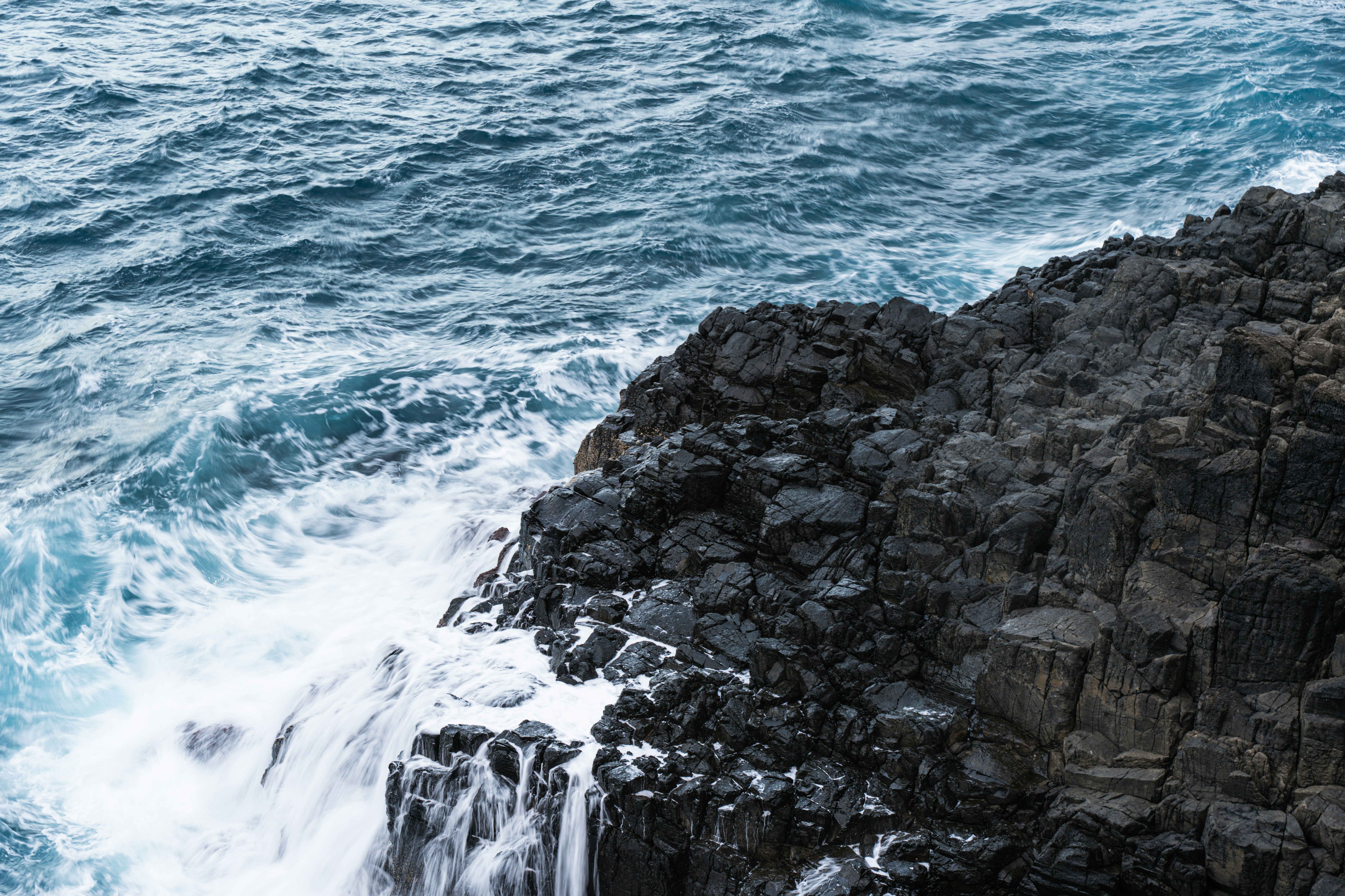 Rugged Coastline: Dark basalt cliffs Meet Cerulean Swells