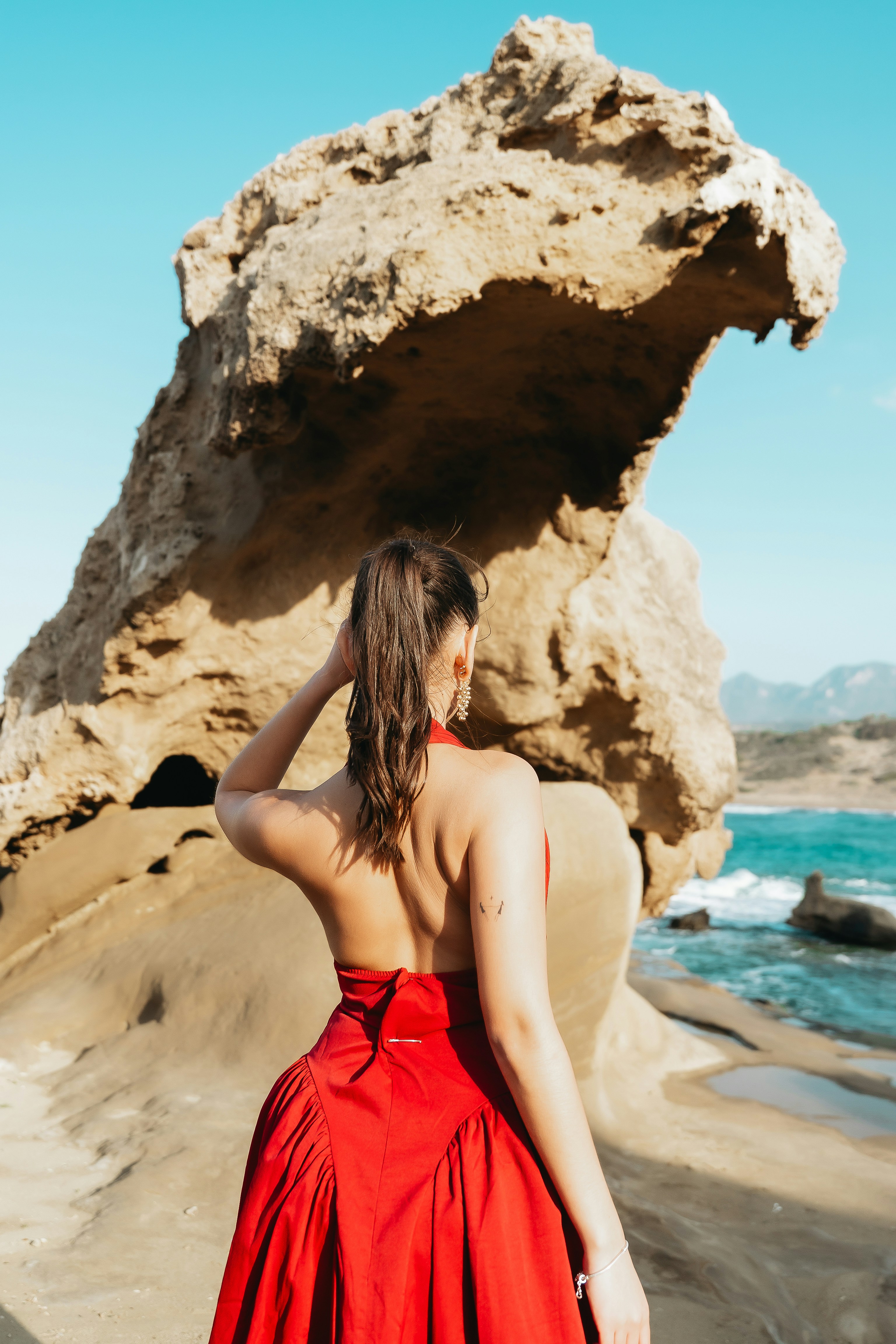 Red-draped silhouette against a sculpted coastal arch