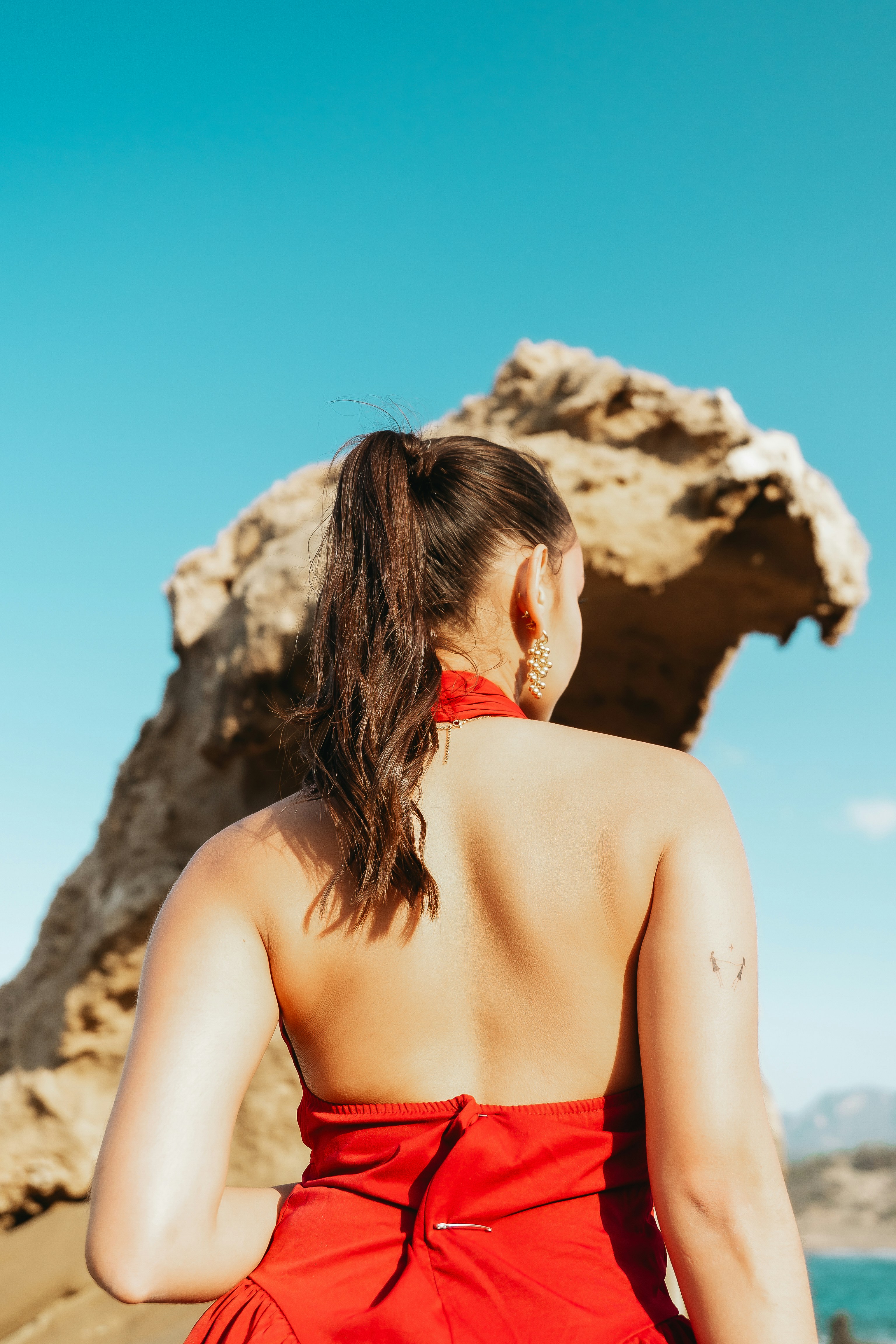 Red Halter, Blue Sea: A Back View in Coastal Sun