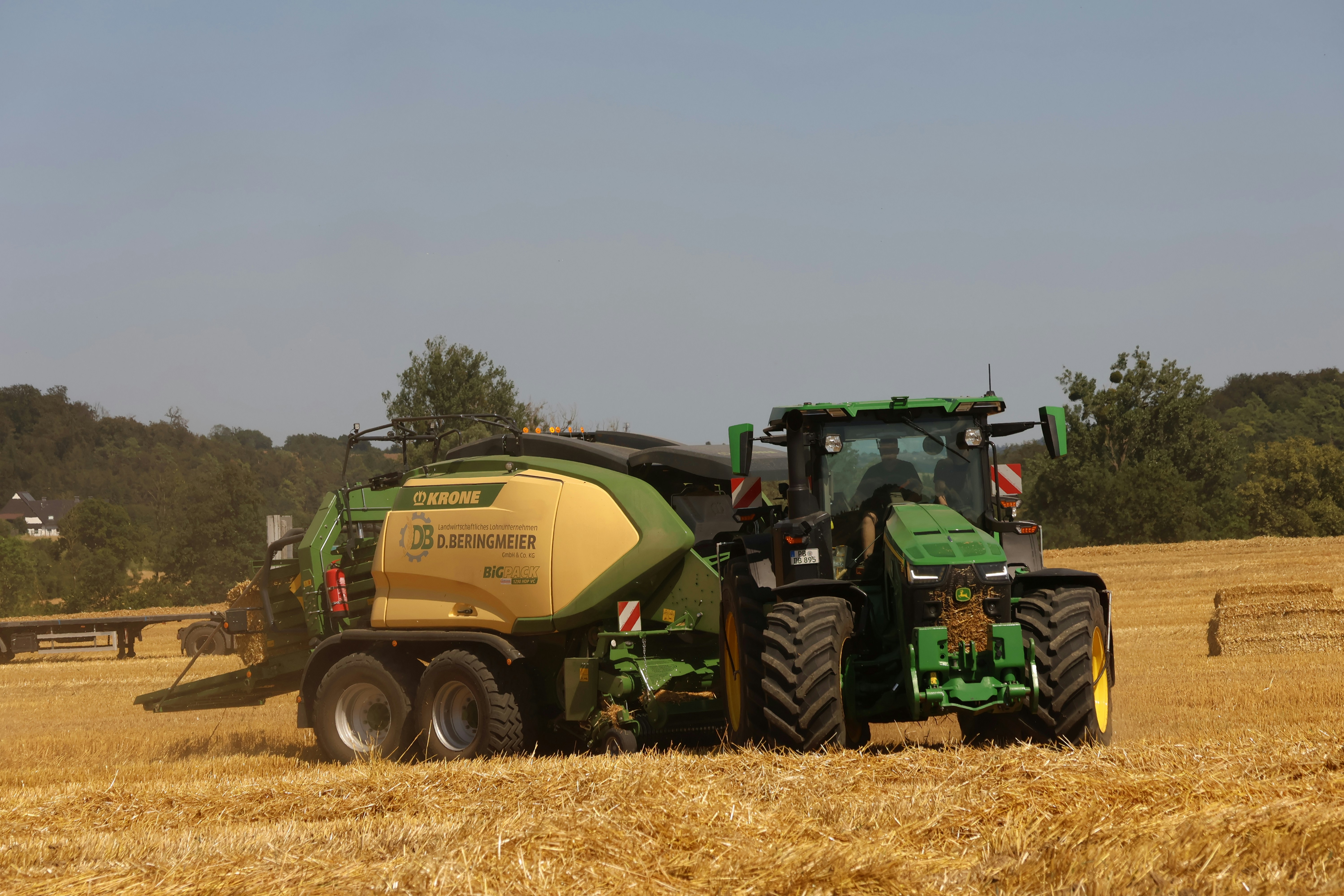 Green Harvest Duo: Tractor and Baler in a Sunlit Field