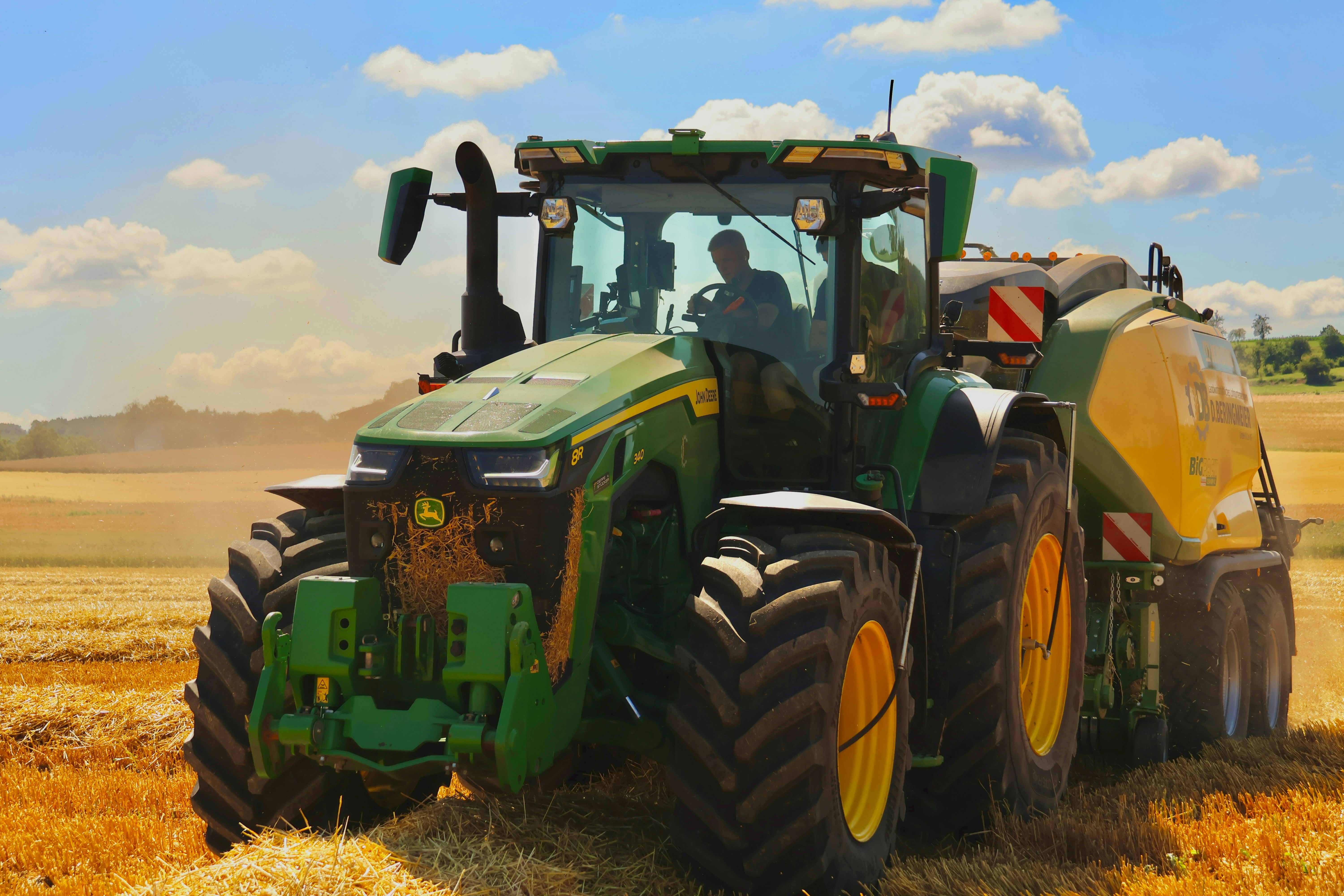 Harvest Giant: Green Tractor Pulling a Yellow Baler Through Golden Field
