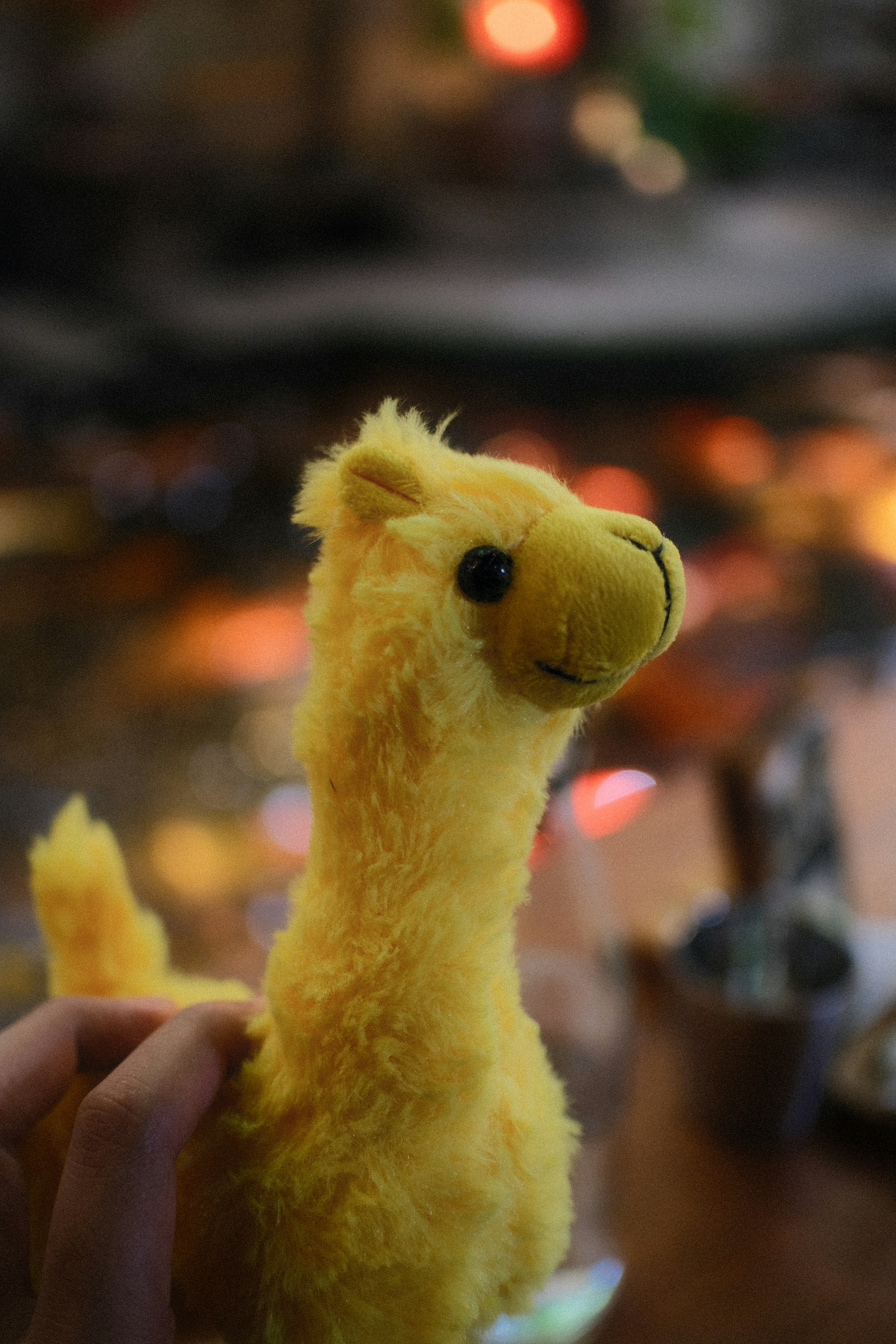 A yellow llama plush toy held by a hand.
