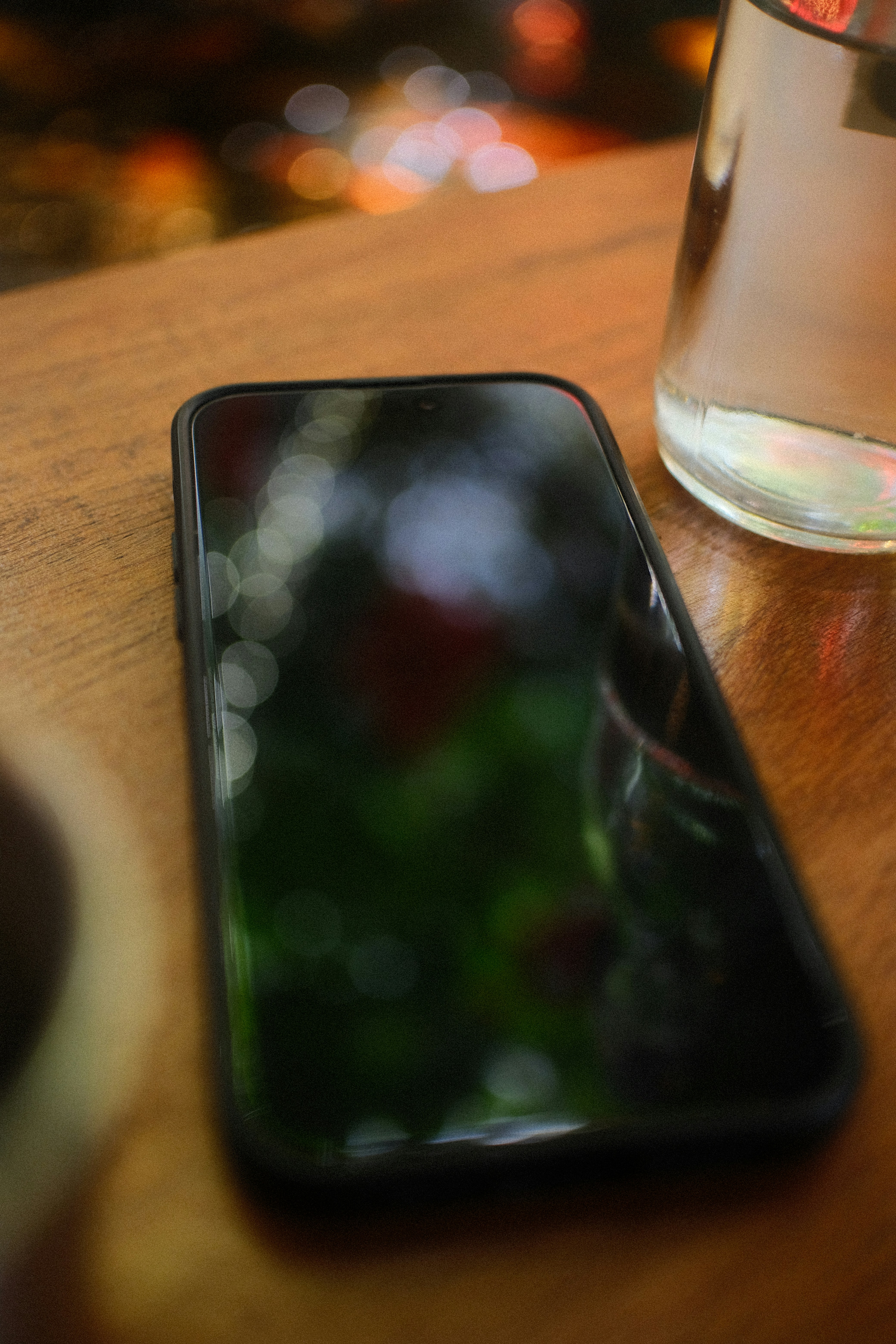 Blurred Glass and Warm Wood: A Quiet Moment with a Smartphone