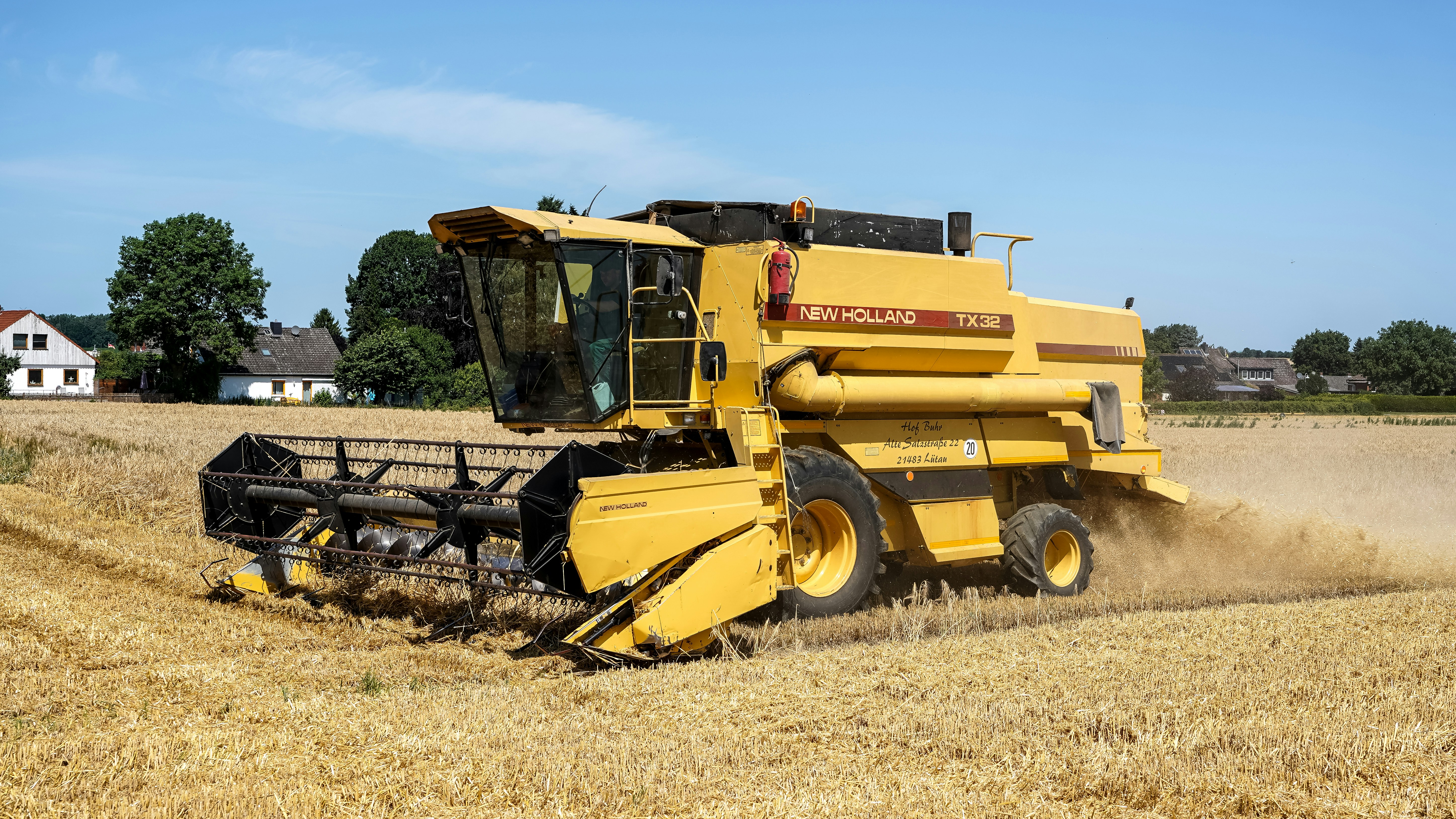 Golden Harvest: A New Holland Combine Reaps the Field Under a Clear Sky