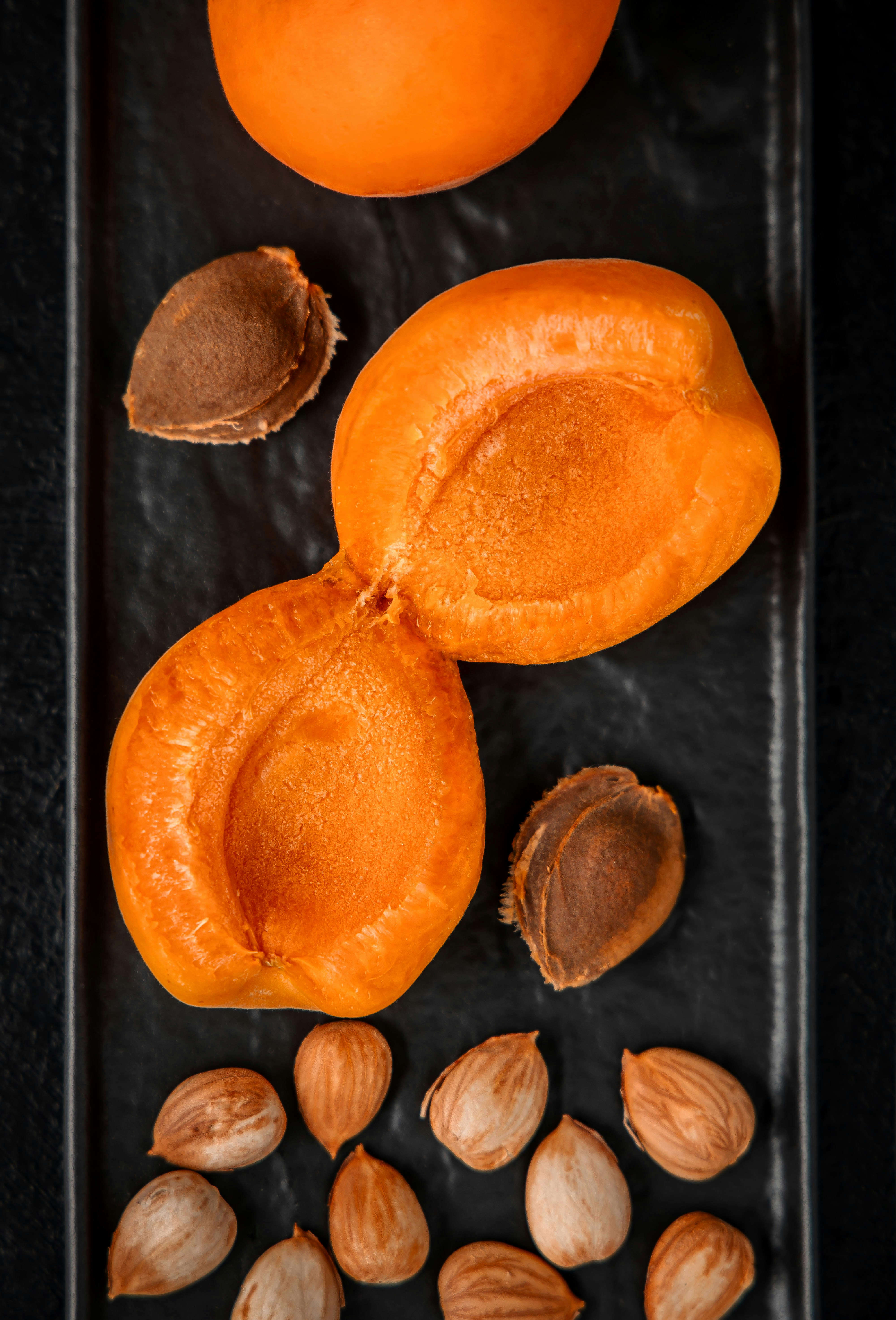 Crunchy Seeds and Peaches: A Close-Up of Apricot Nuclei on a Dark Tray