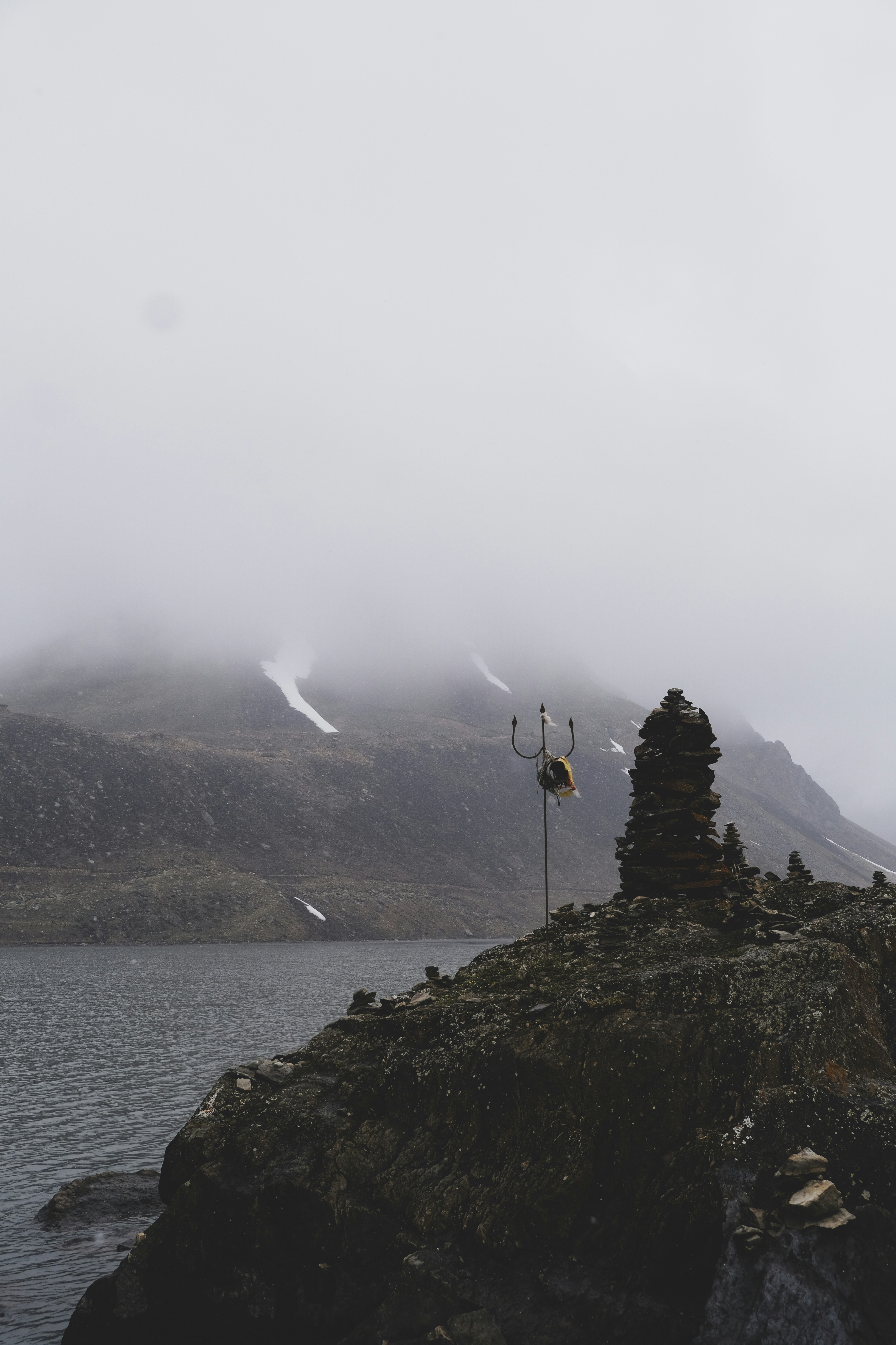 Lone beacon on a rugged promontory beneath misty peaks
