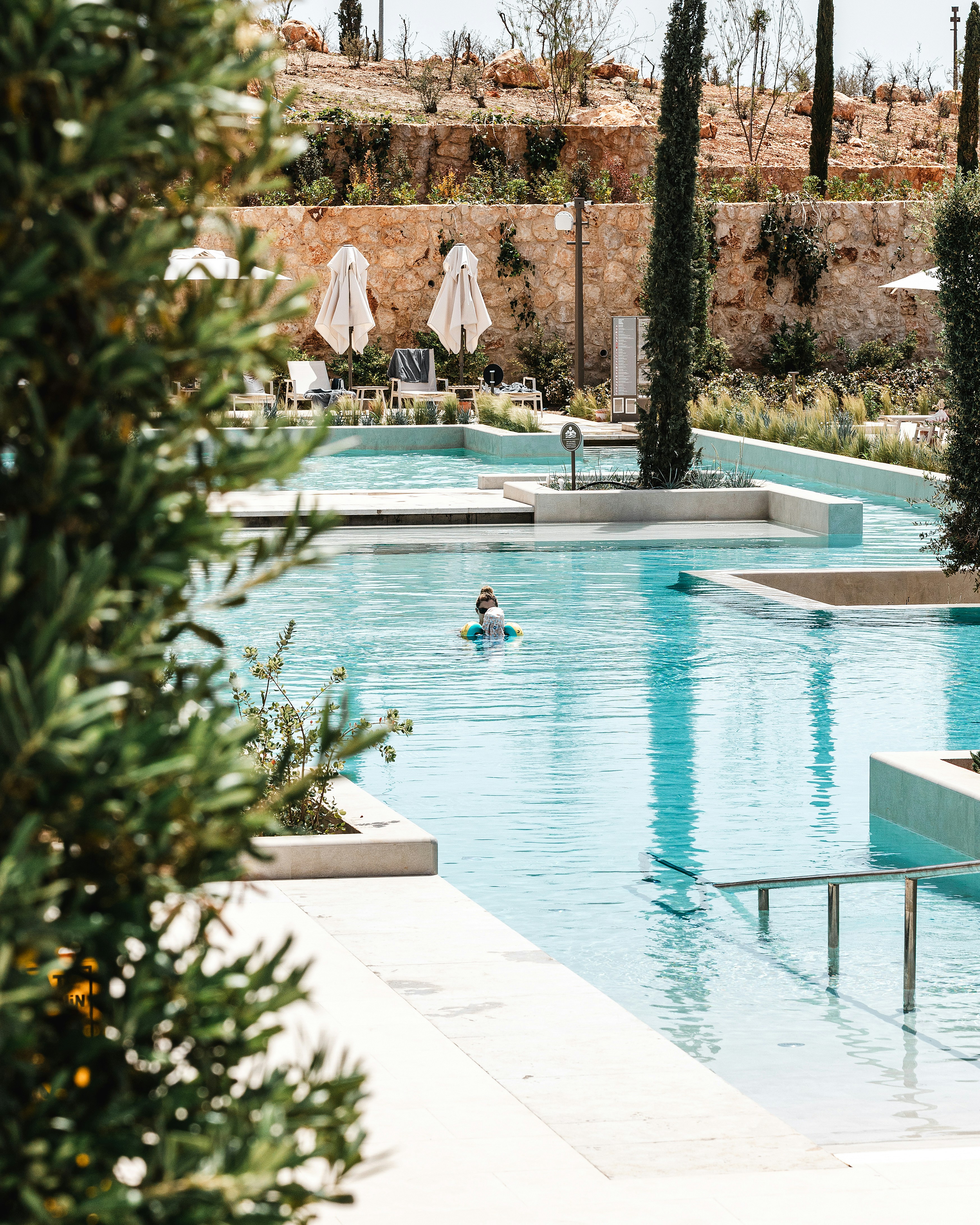 Solitary swimmer beneath a sunlit courtyard pool