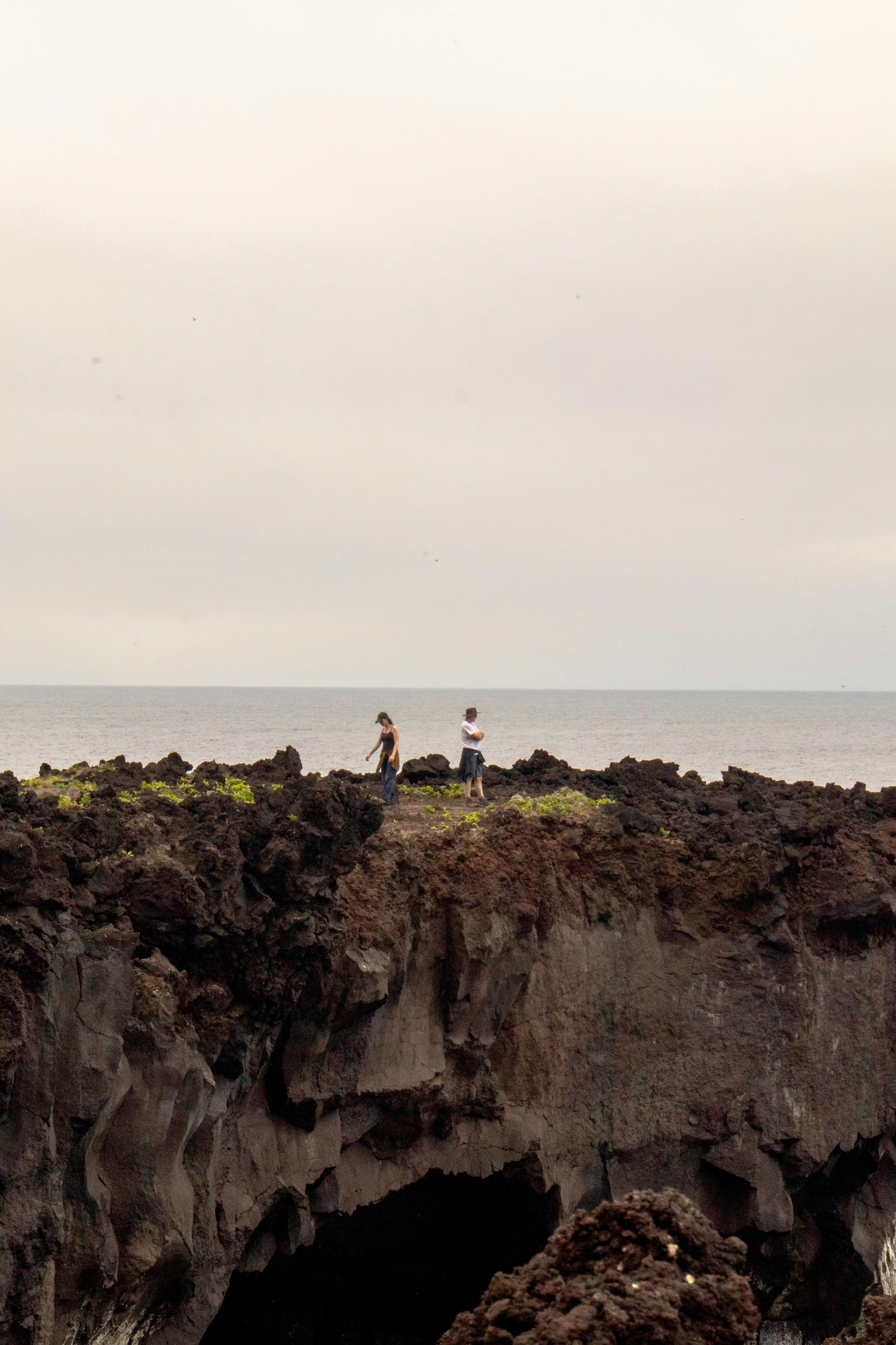 Two Figures on a Rugged Coastline at Distant Horizon