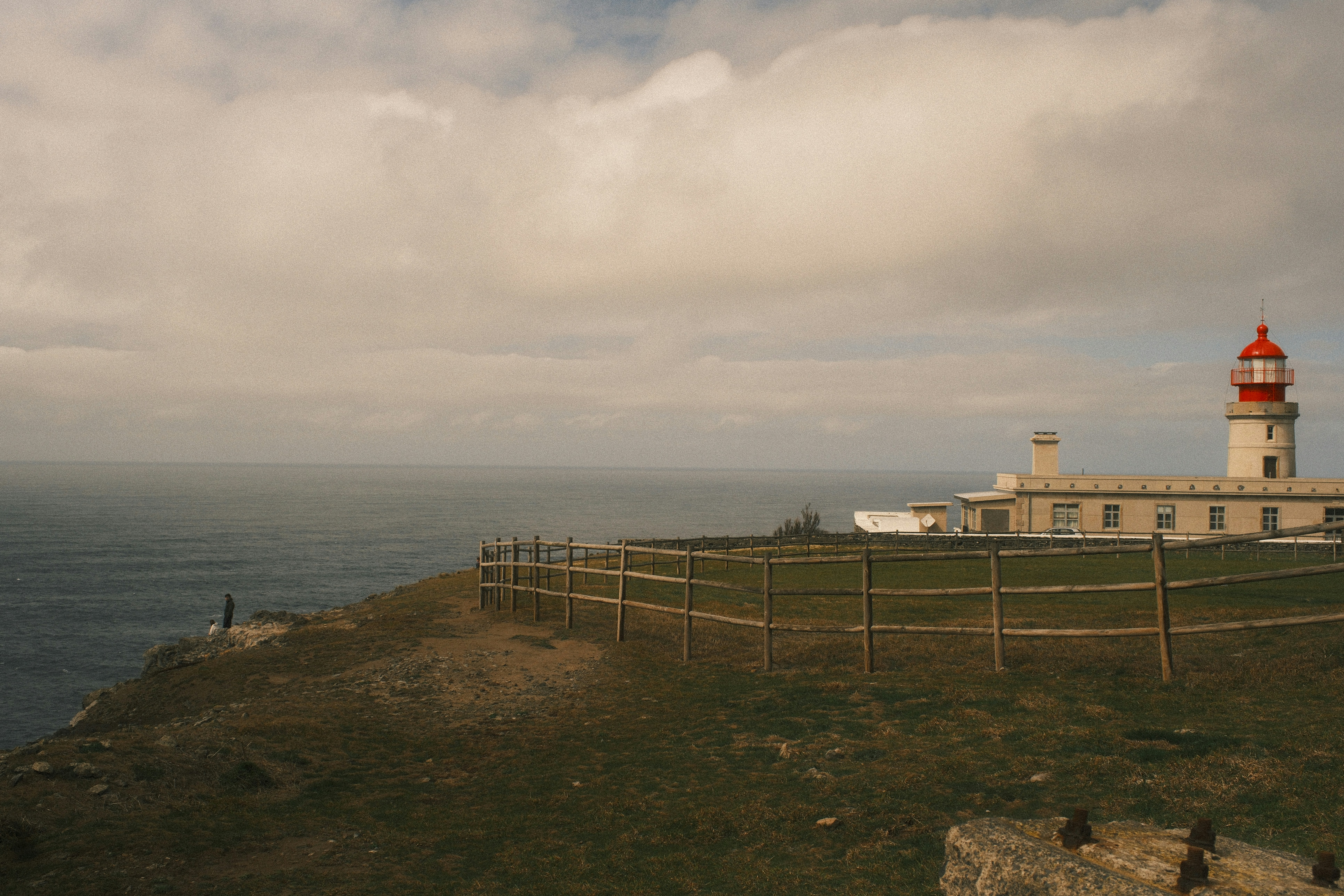 Lighthouse Edge: Calm Coastline over a Fenced Clifftop