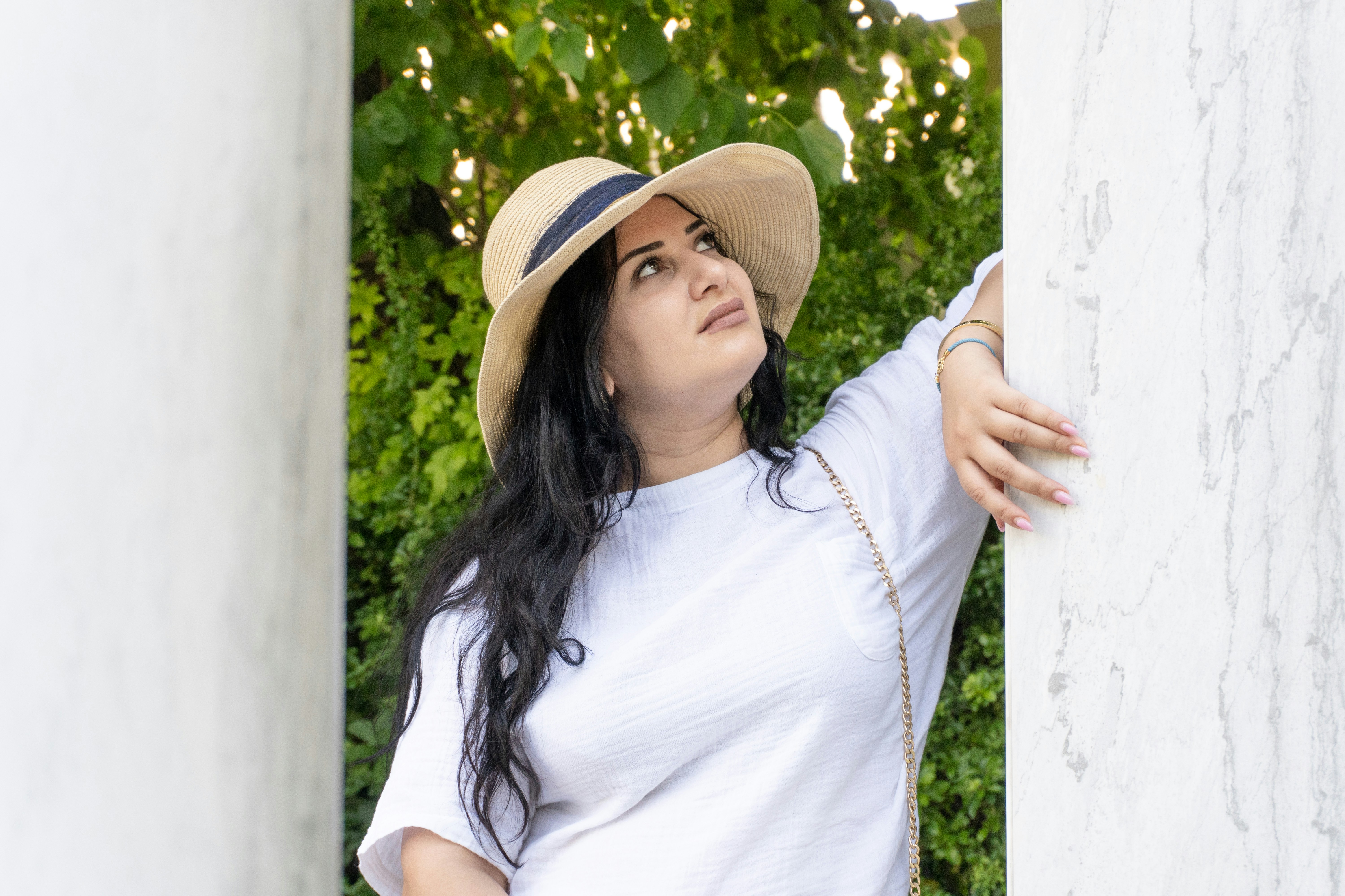 Portrait between Columns: A Sunlit Moment with a Wide-Brimmed Hat