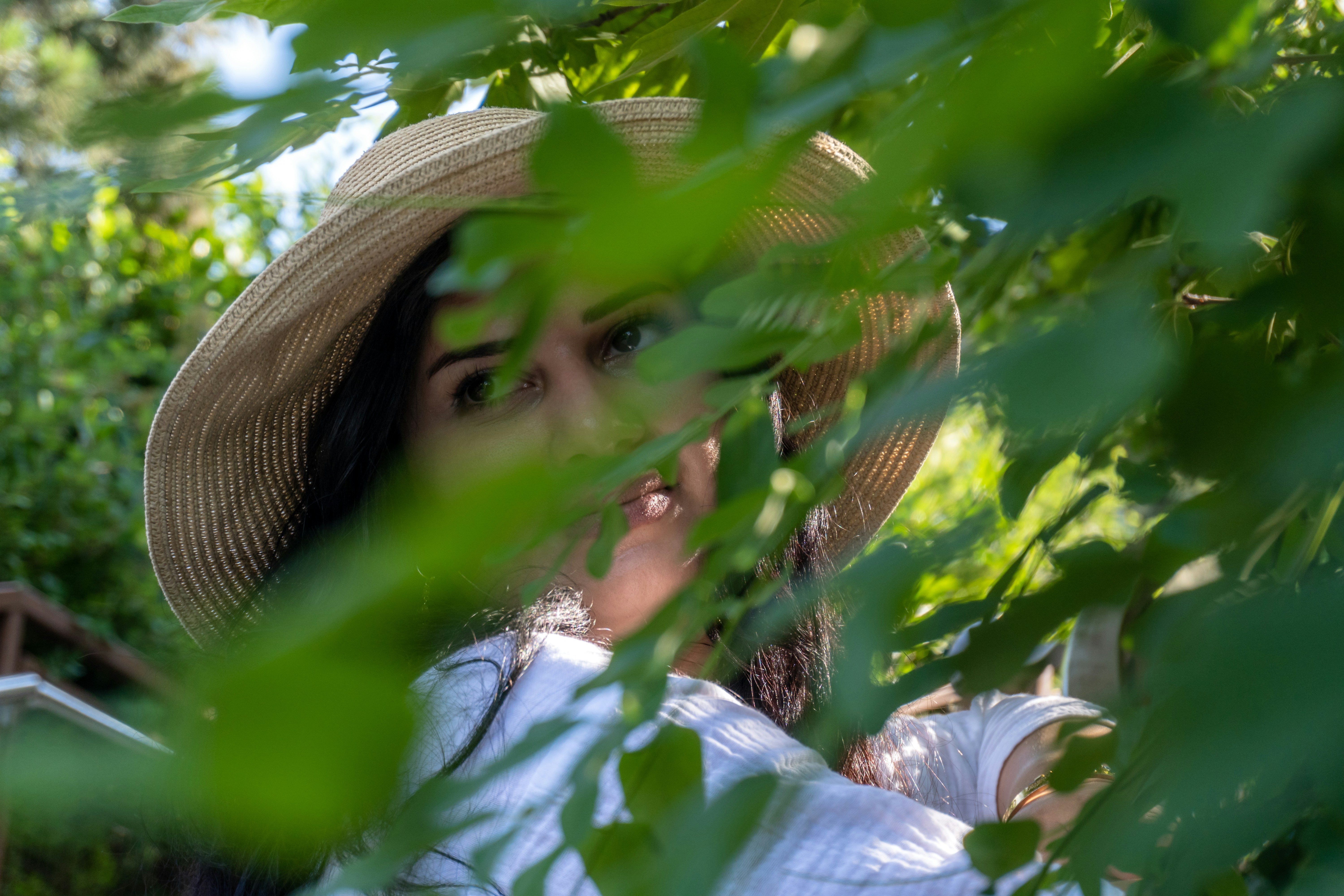 Hidden Smile in the Leaves: A Sunlit Portrait Framed by Foliage