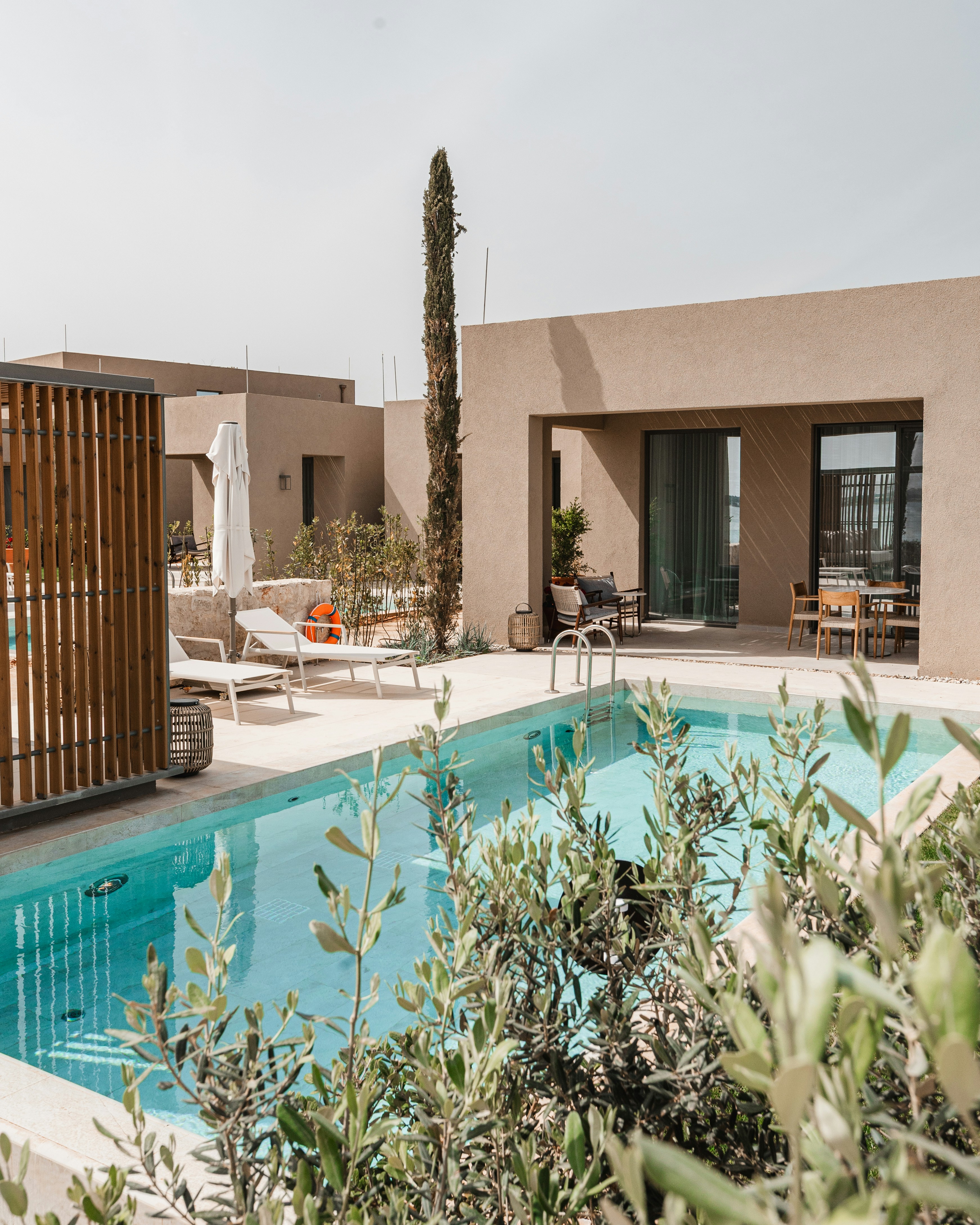 Modern building with a swimming pool and lounge chairs.