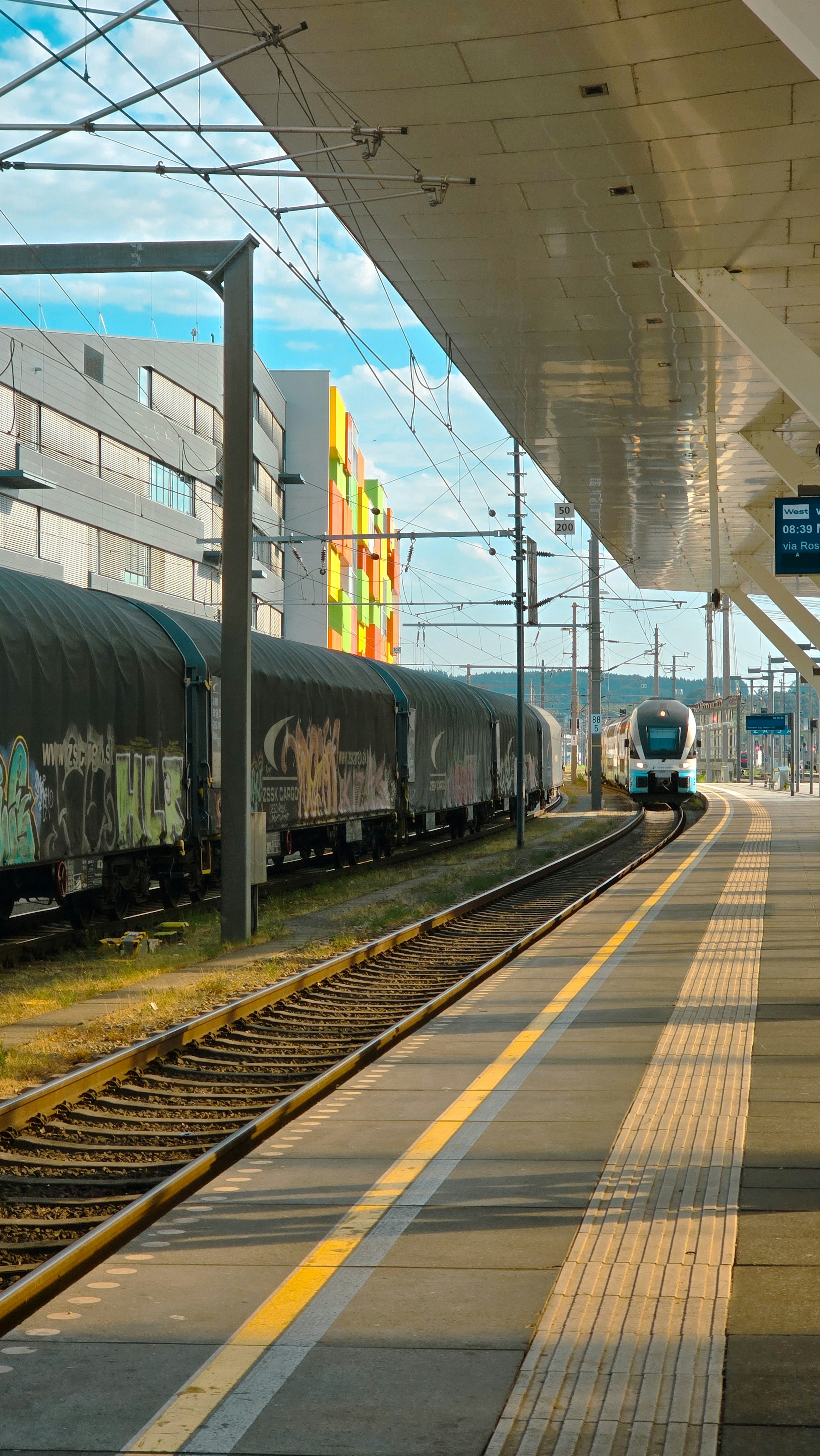 Urban railway line: a sleek train approaches under a modern platform canopied by geometric architecture