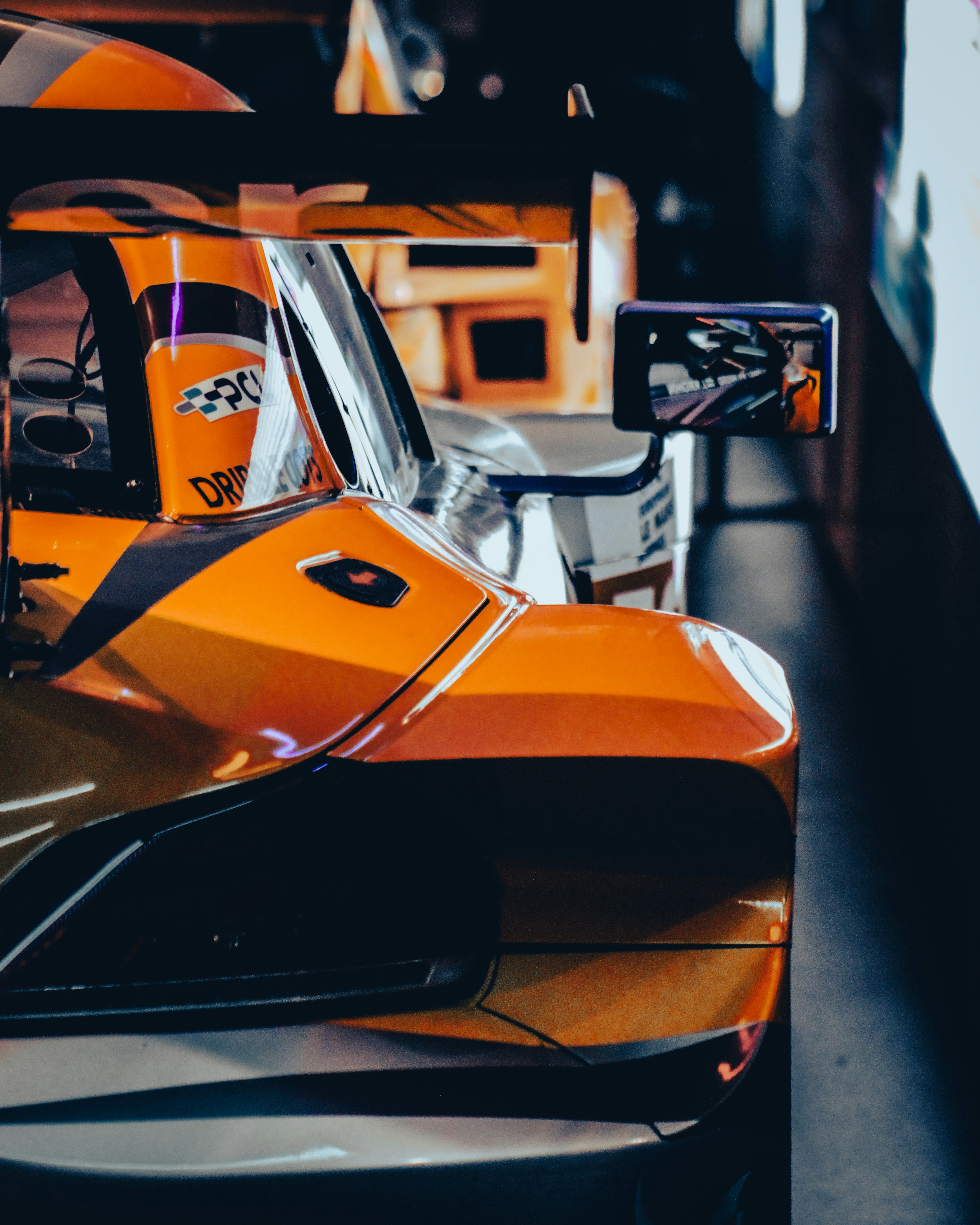 Orange race car in a display workshop, close-up of the nose and cockpit
