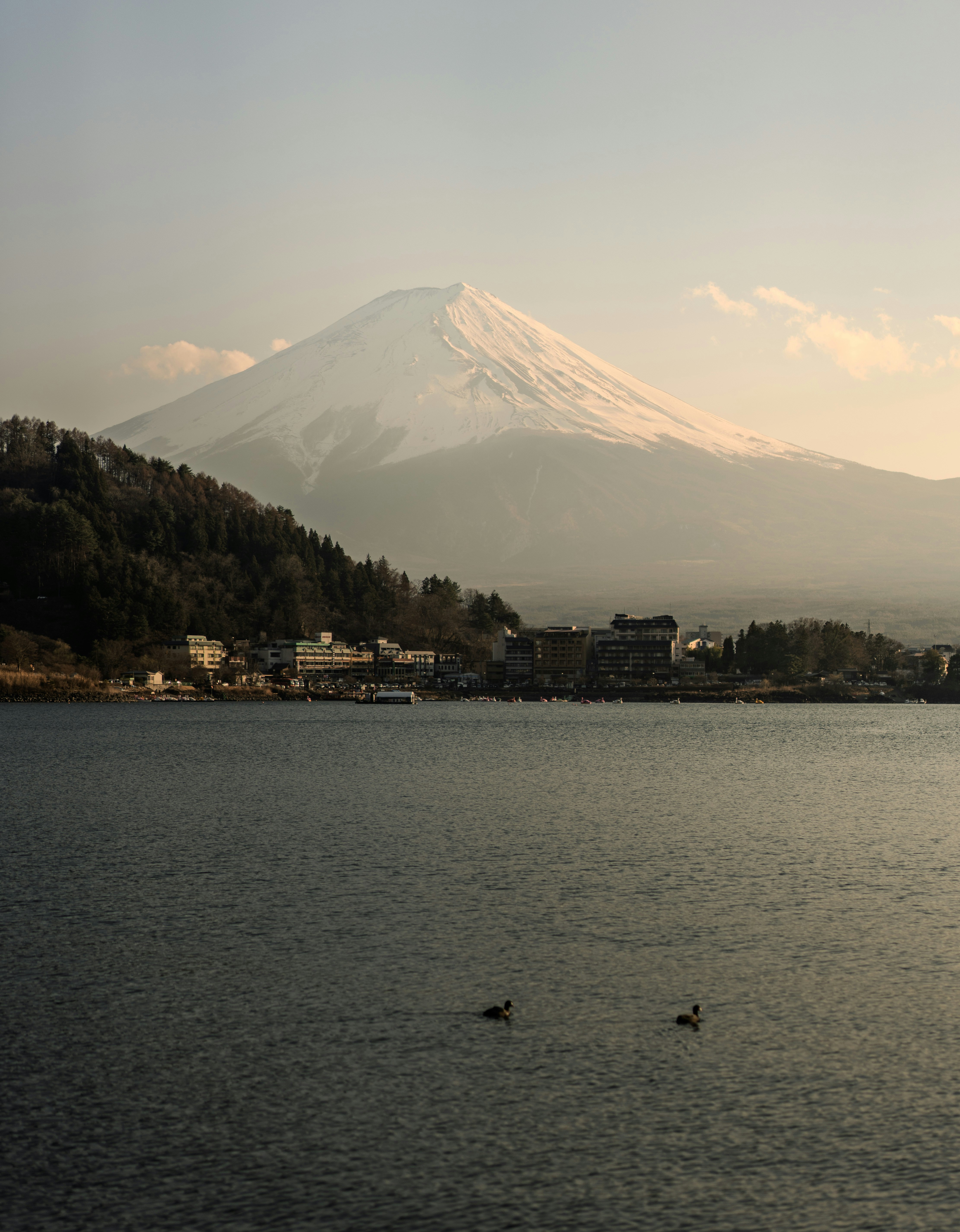 Snow-capped Mount Fuji over a tranquil lakeside village at sunset