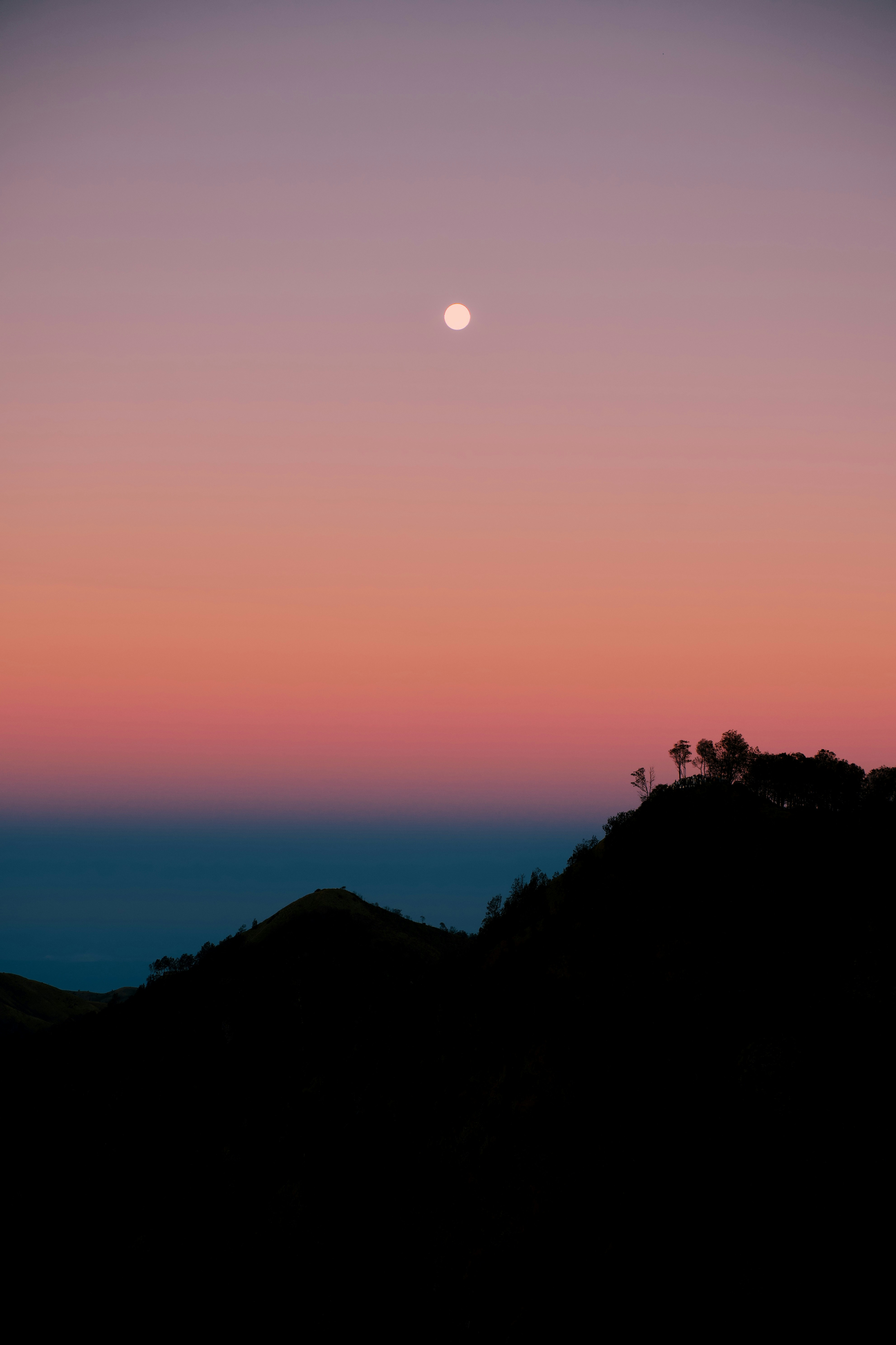 Moonrise over the silhouetted ridge at dusk