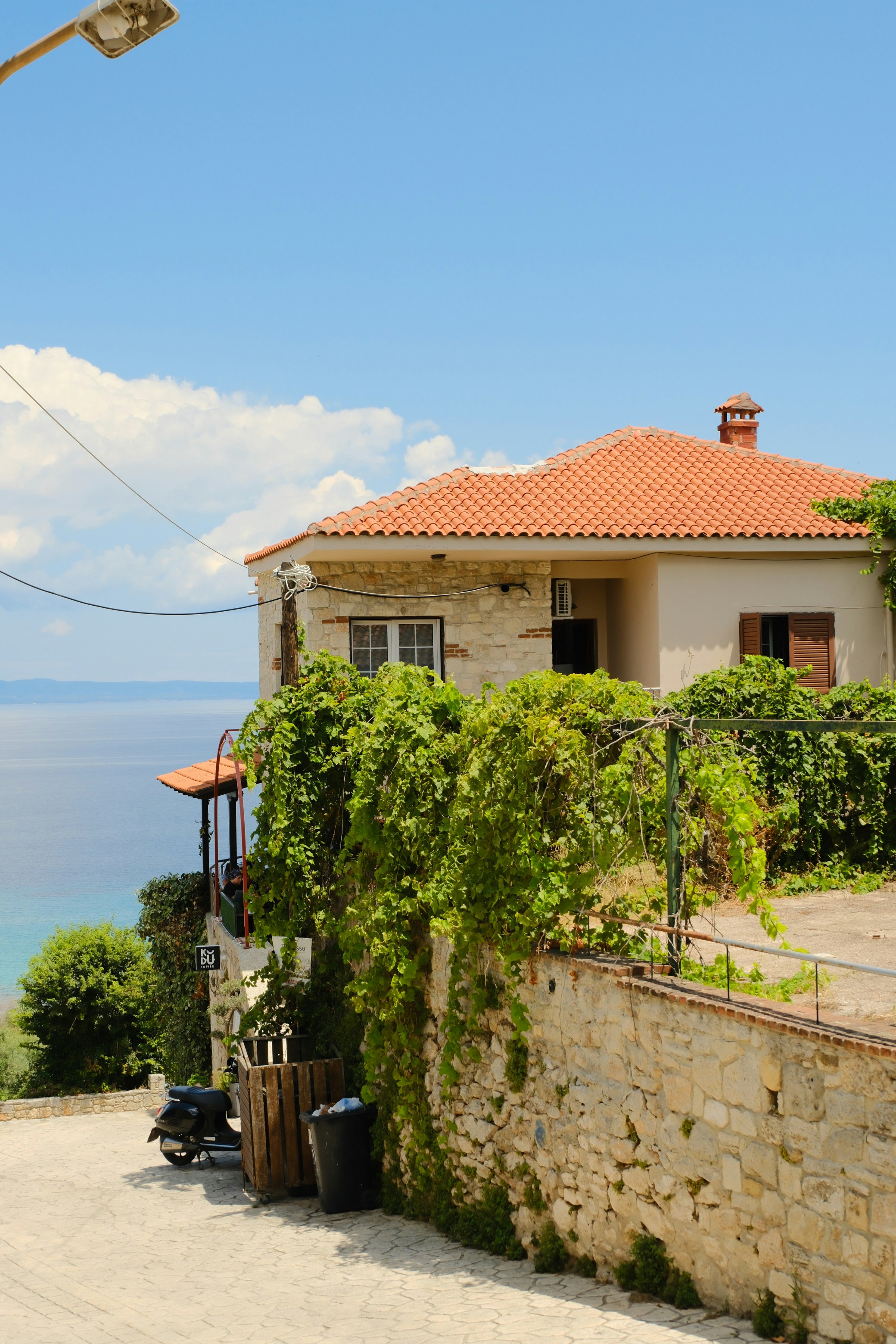 Sunlit Terrace Overlook: Mediterranean House Framed by Vine-Covered Stone Wall