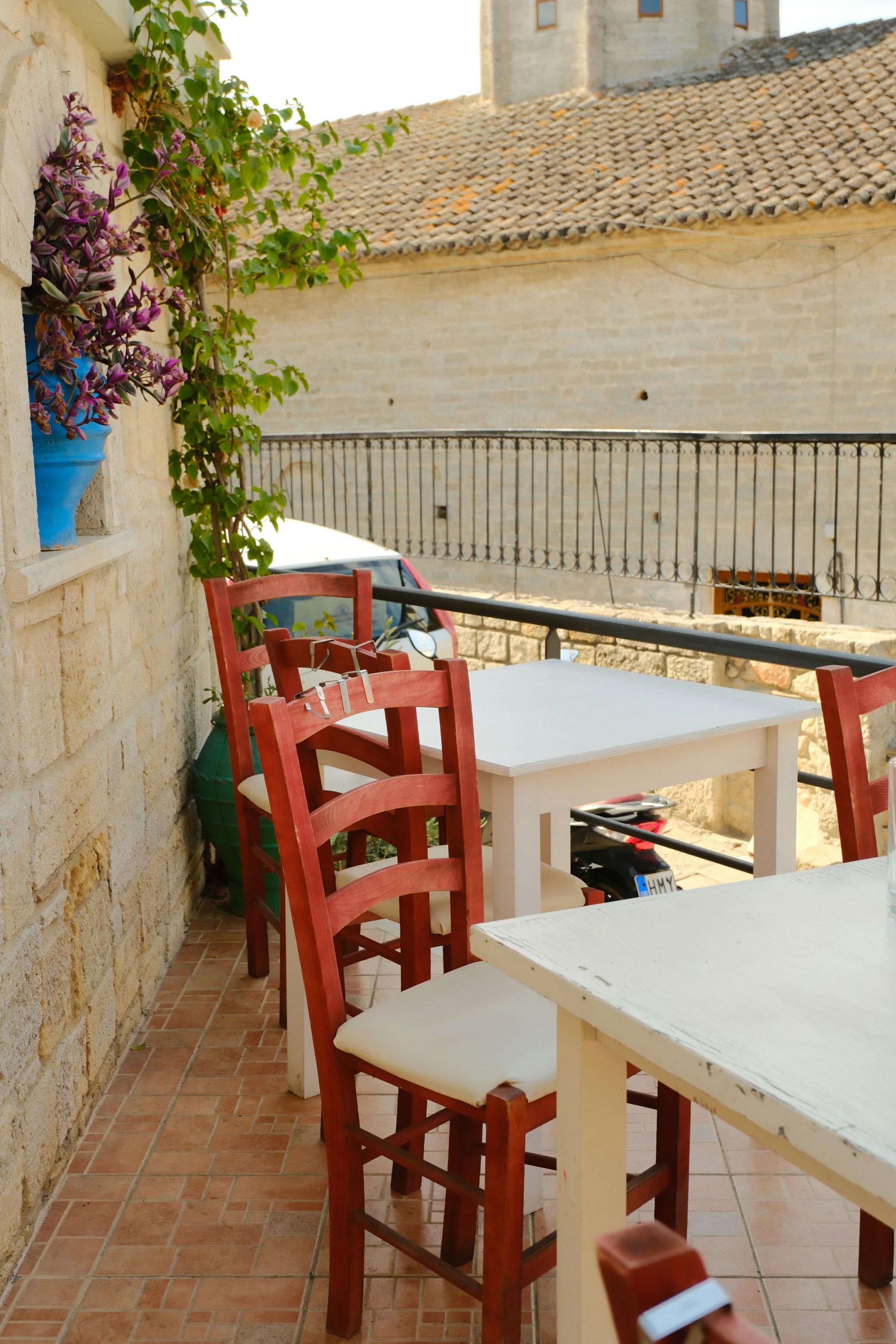 Sunlit Terrace with White Tables and Red Chairs