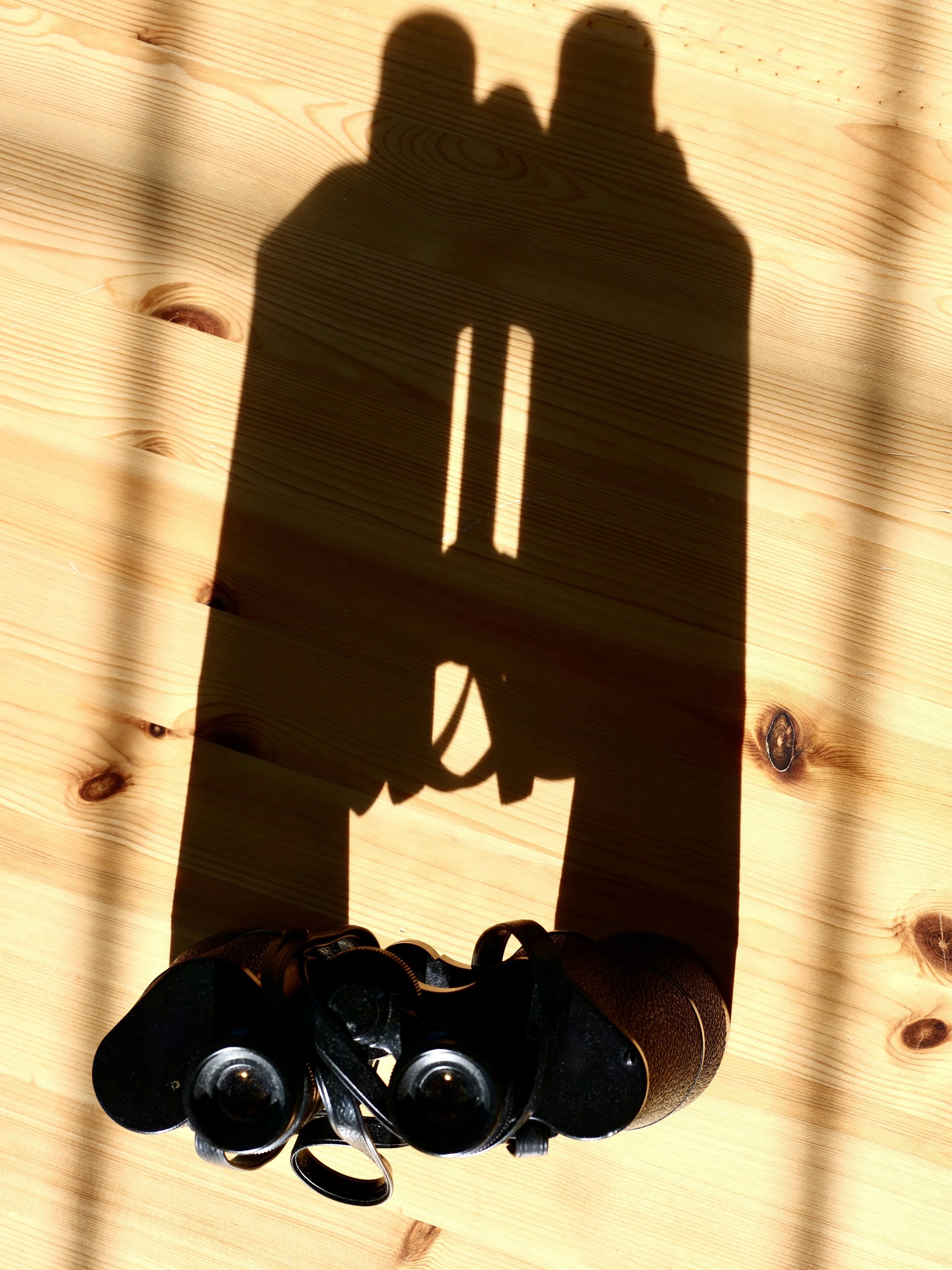 A binocular and its shadow on a wooden table