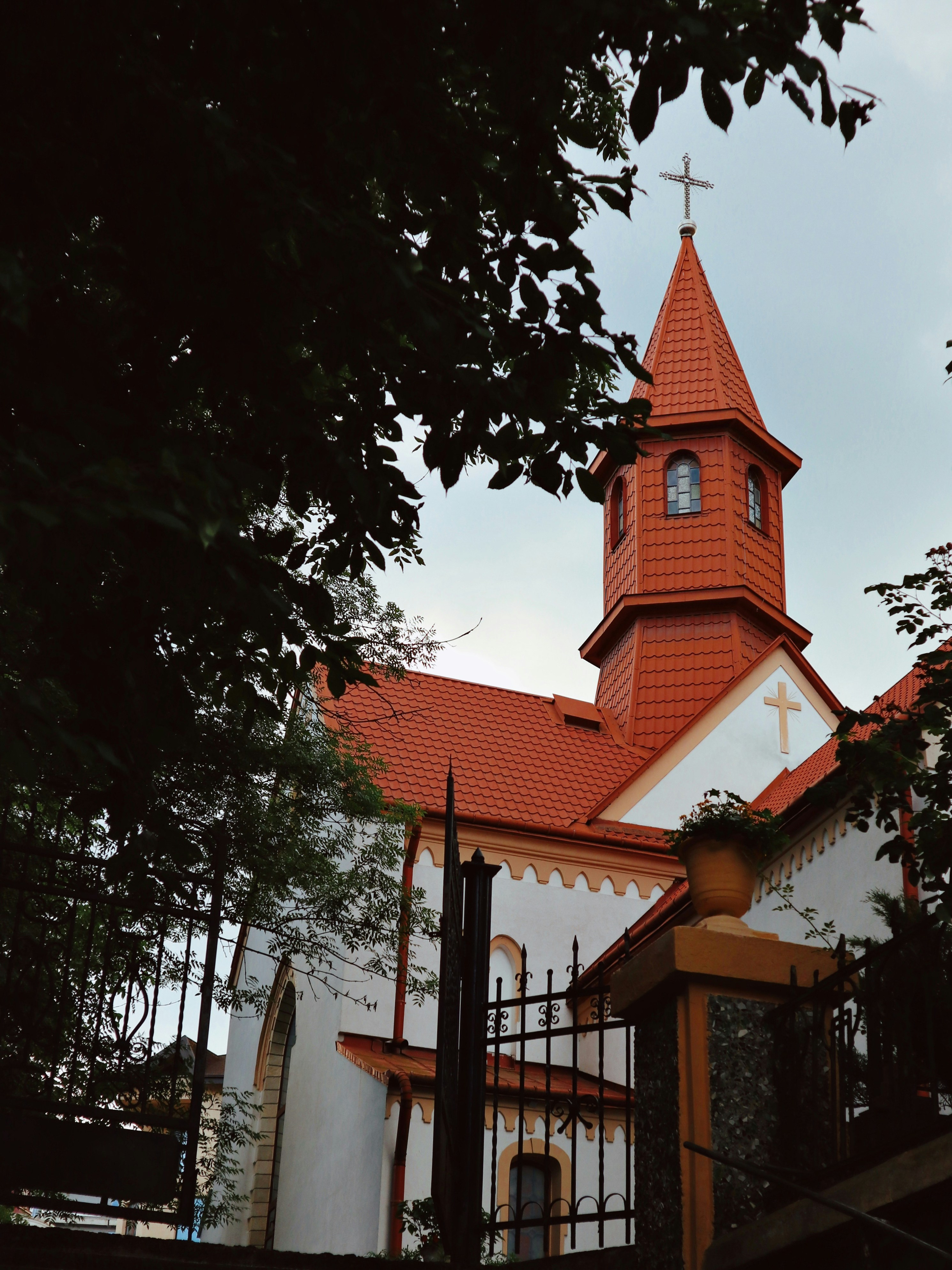 Red-tiled Church with Shadowed Foreground and Iron Fence