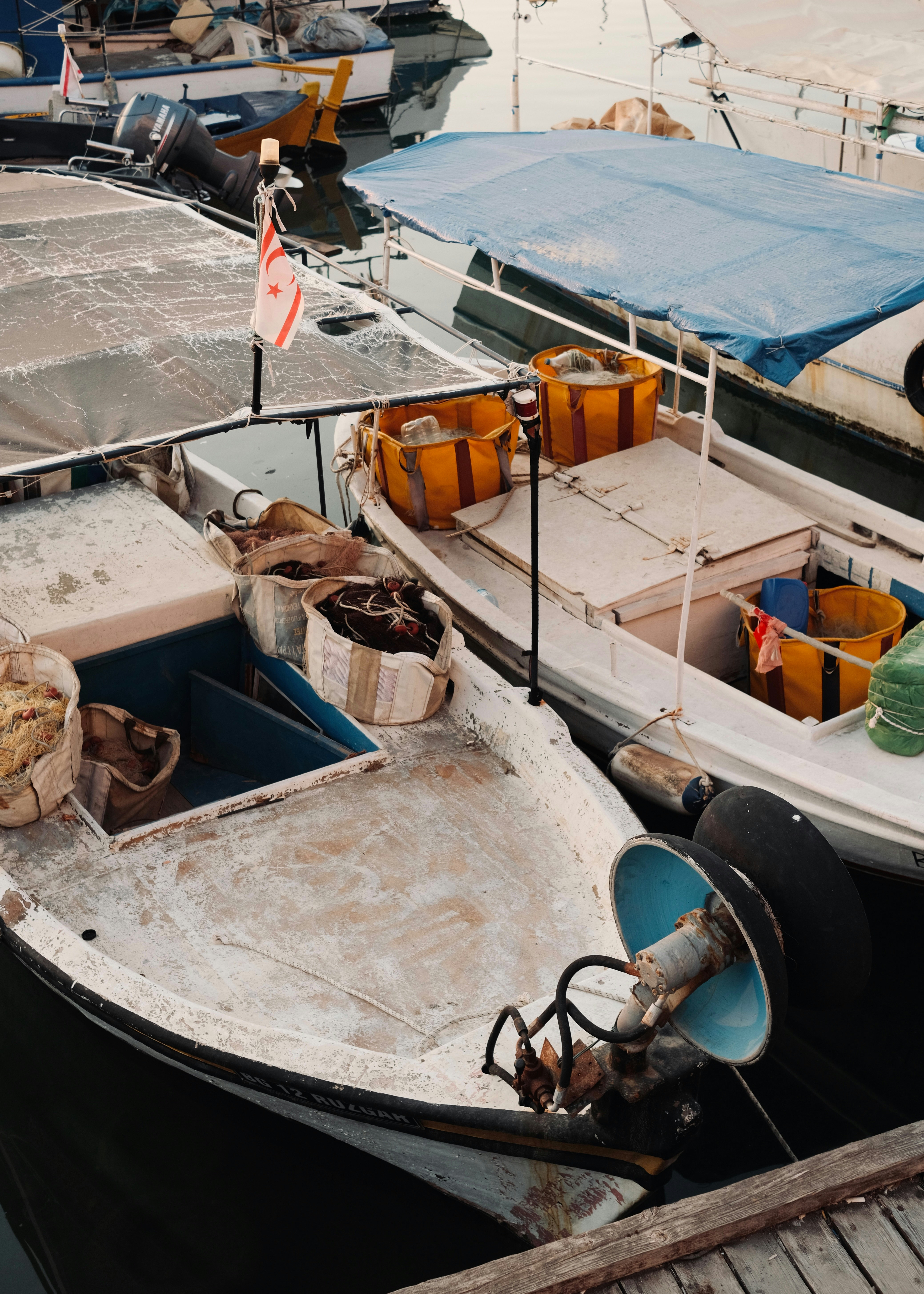 Weathered harbor: a row of moored boats under a blue canopy