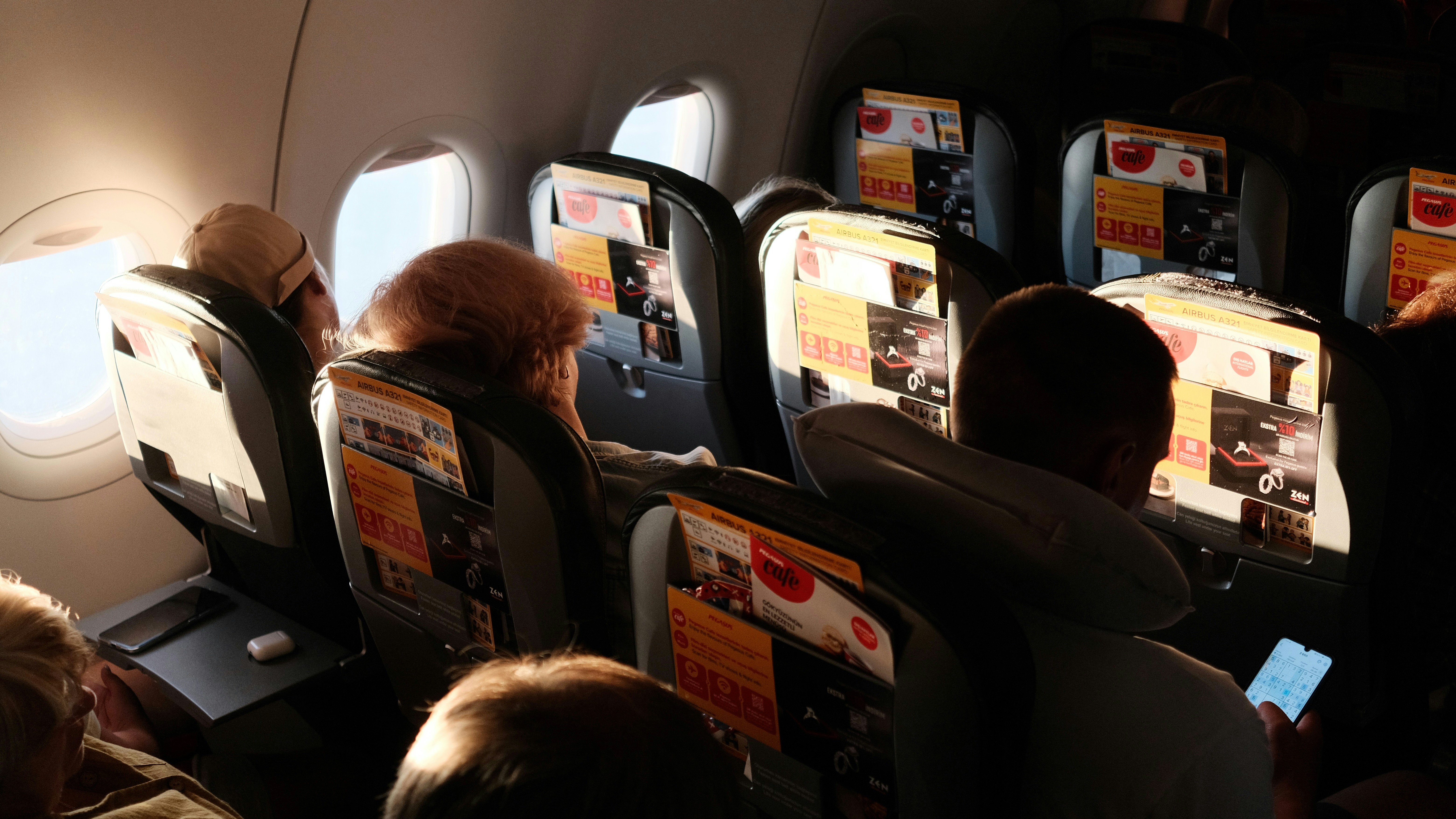 Couple of Aisle-Row Travelers under Flight Attendant Advertisements