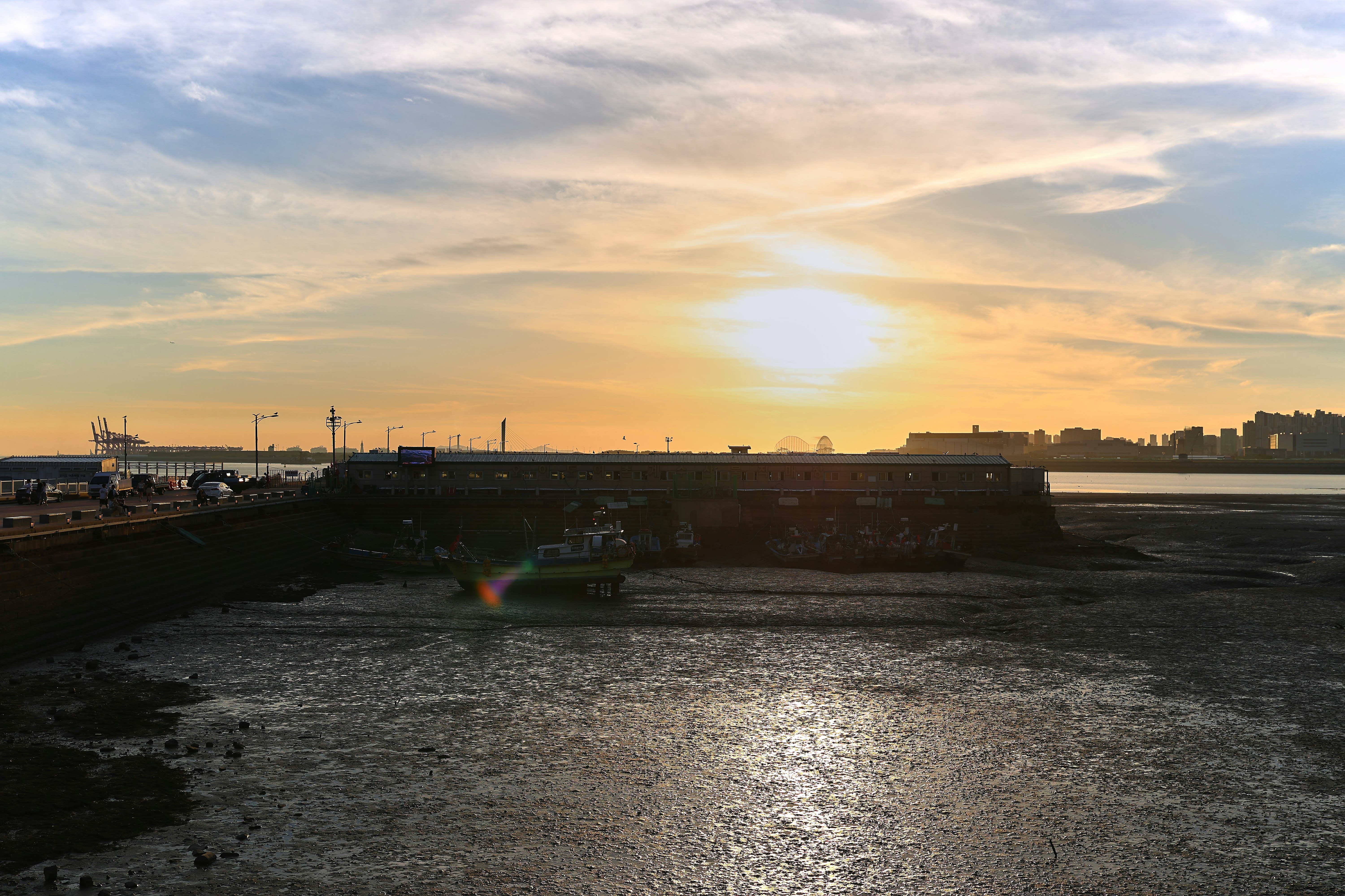 Sunlit Harbor at Dusk: Boats, Breakwater, and a Quiet Sea