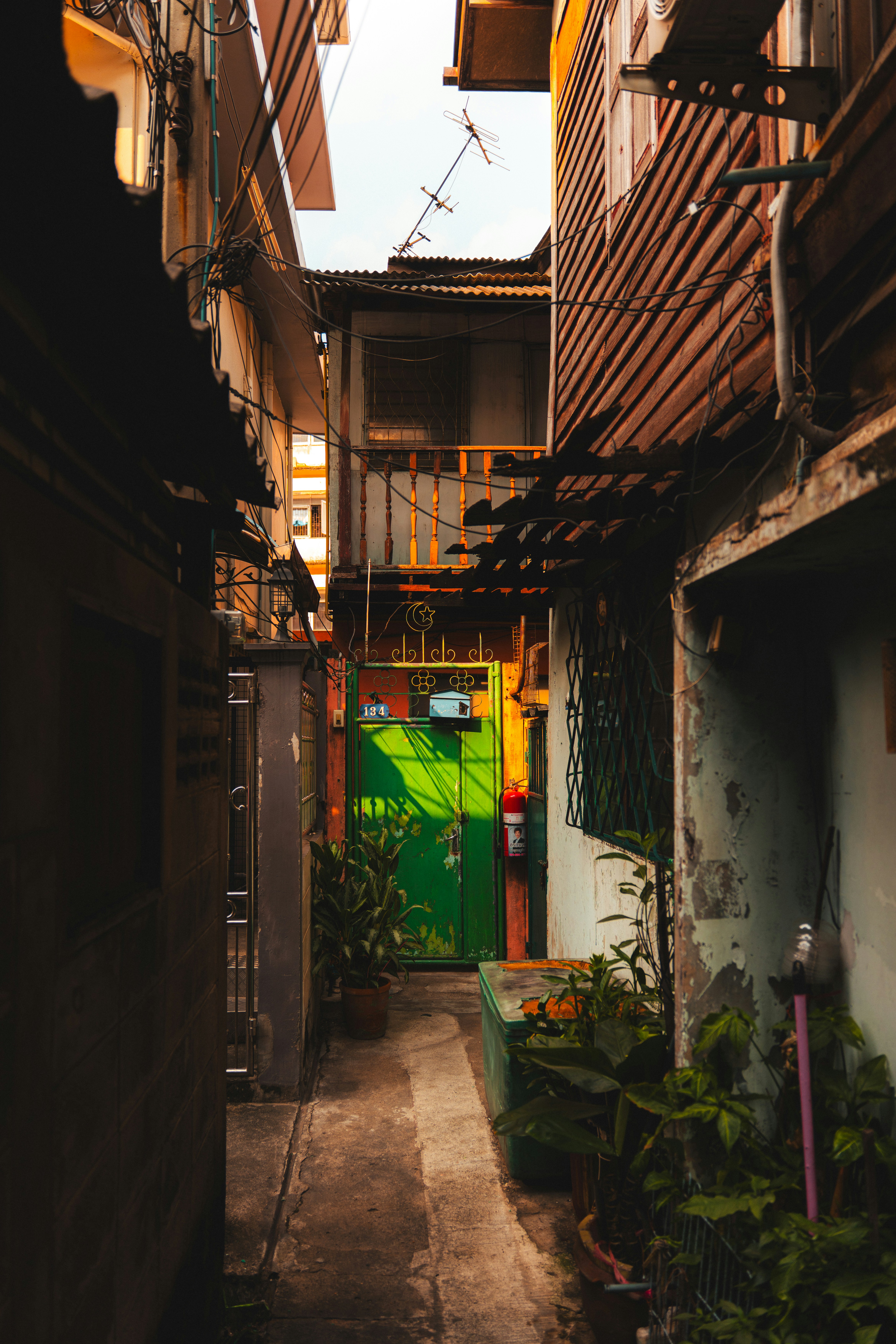 A narrow alleyway leads to a vibrant green door.