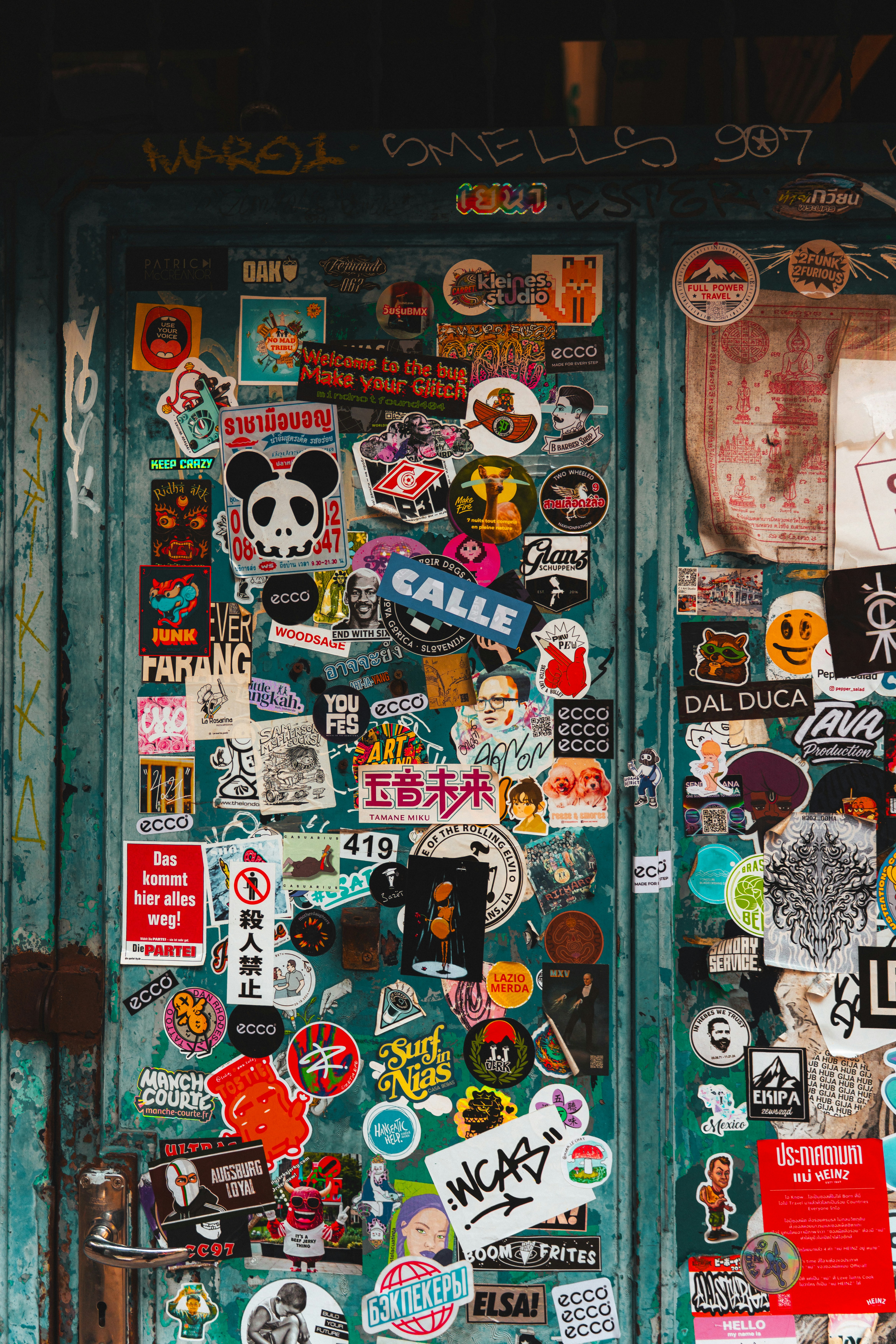 Stickered Portal: A Teal Door Melded with Color and Character