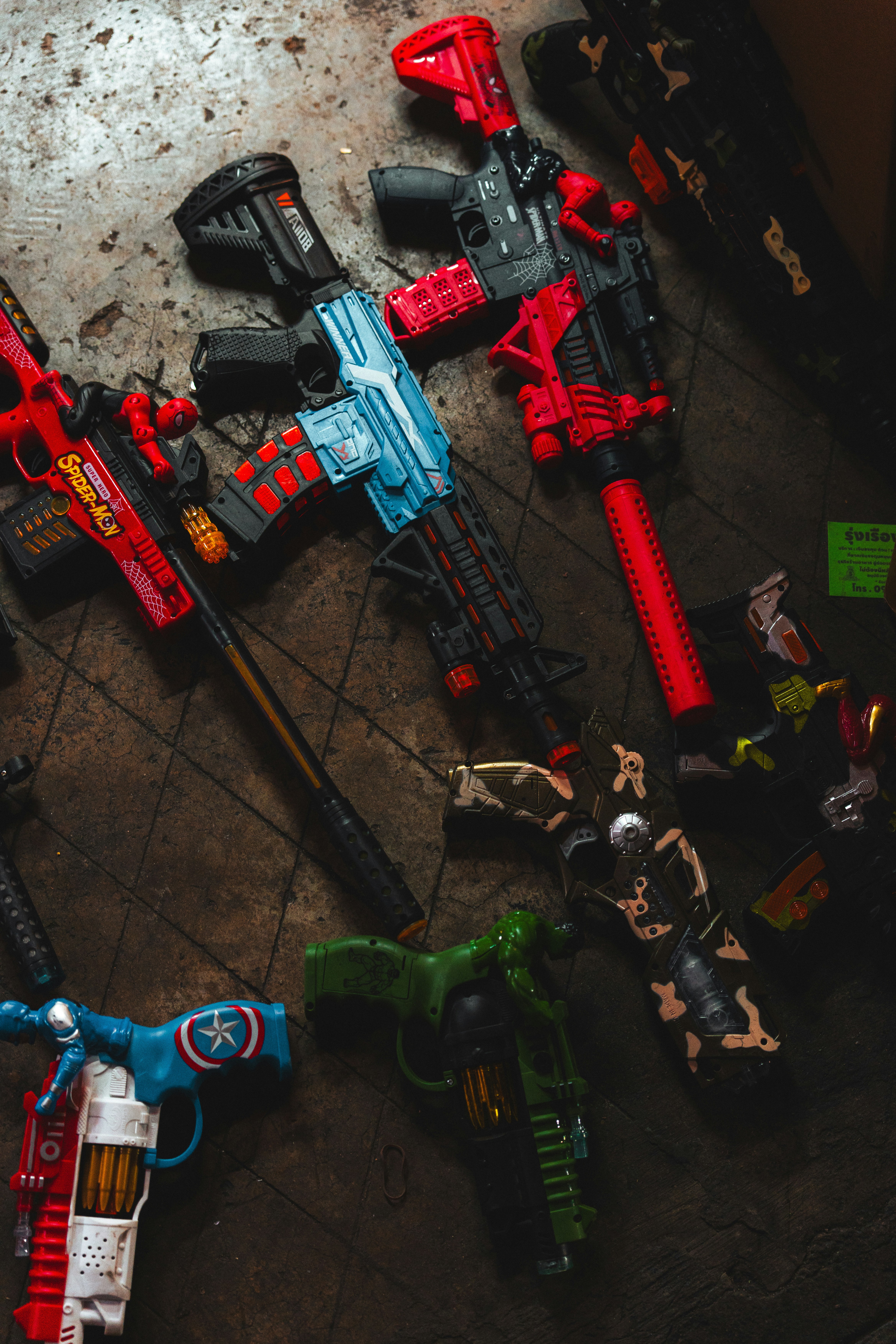A collection of colorful toy guns on a dark surface.