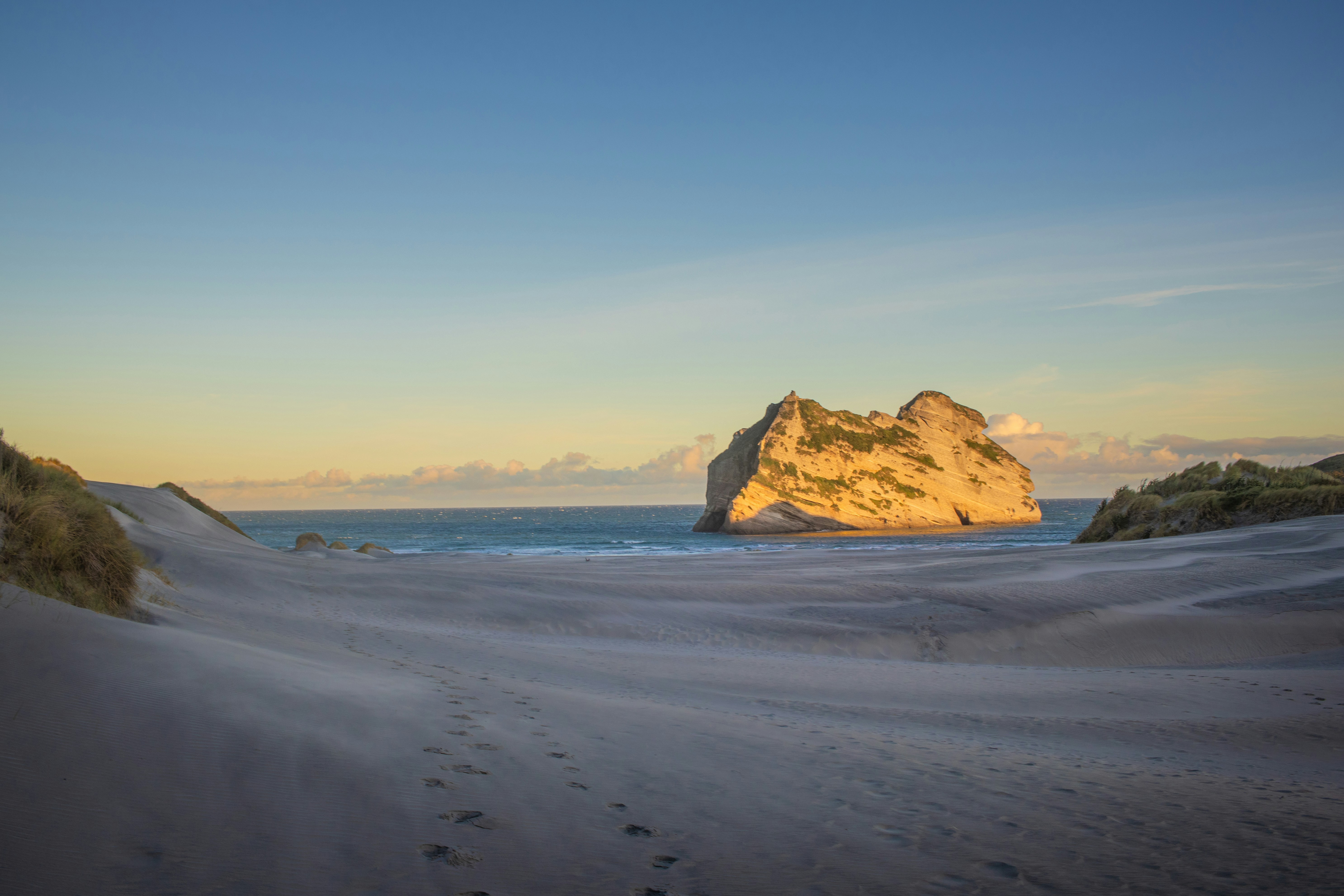 Sunlit Sea Stack Emerges from Quiet Sands