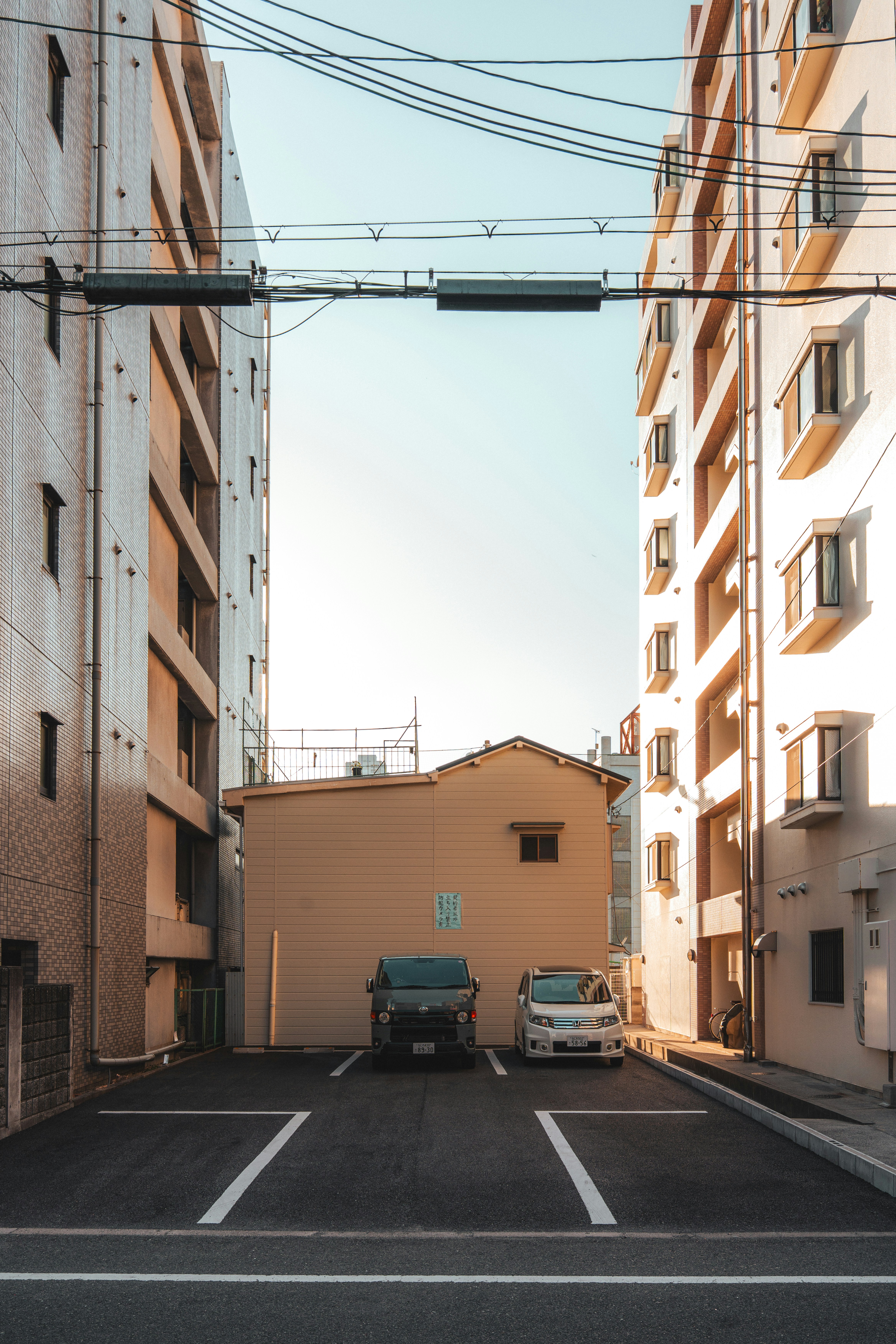 Sunlit alleyway with parked vans framed by urban high-rises