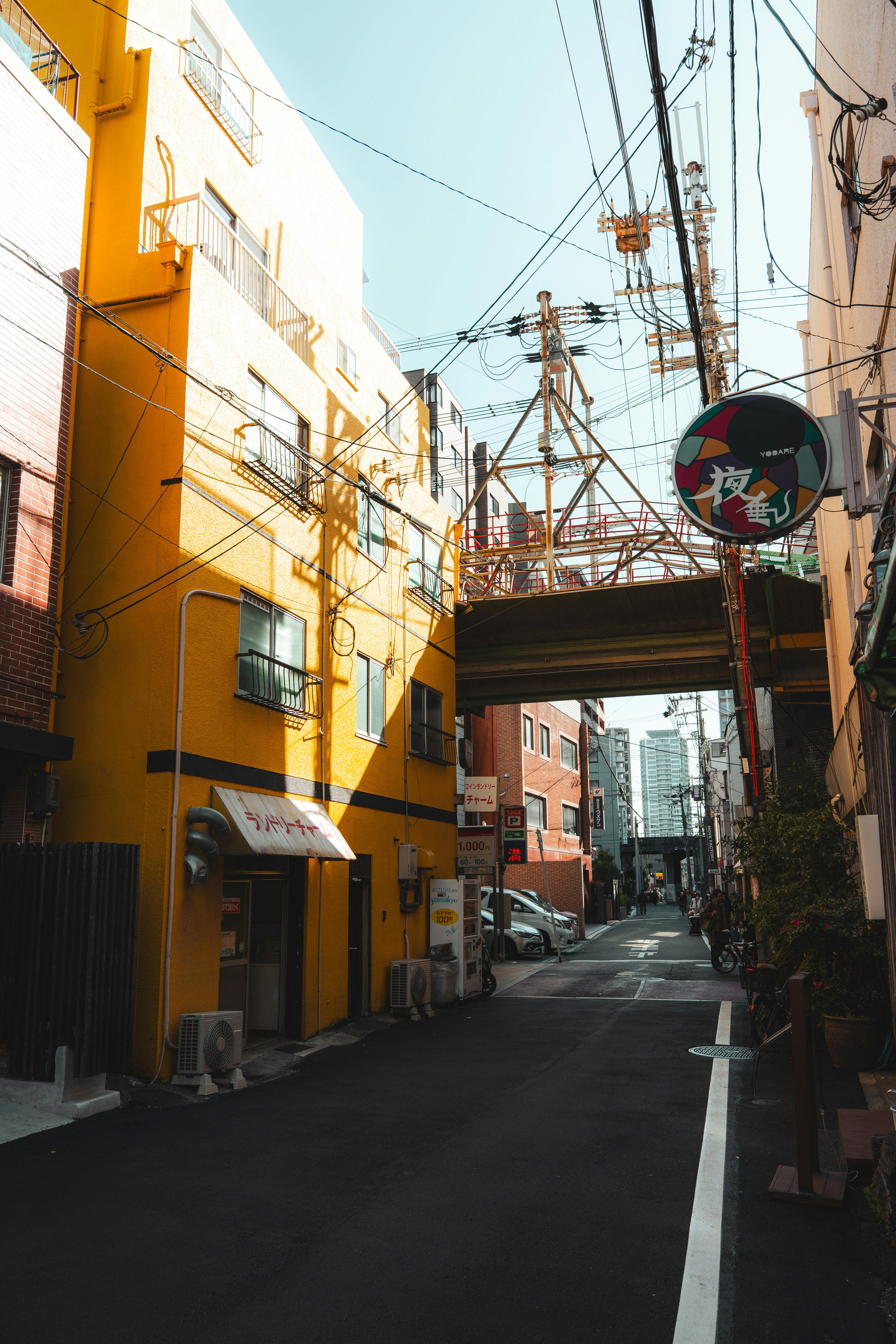 Sunlit Alleyway: Neon Yellow Facades and Overhead Wires