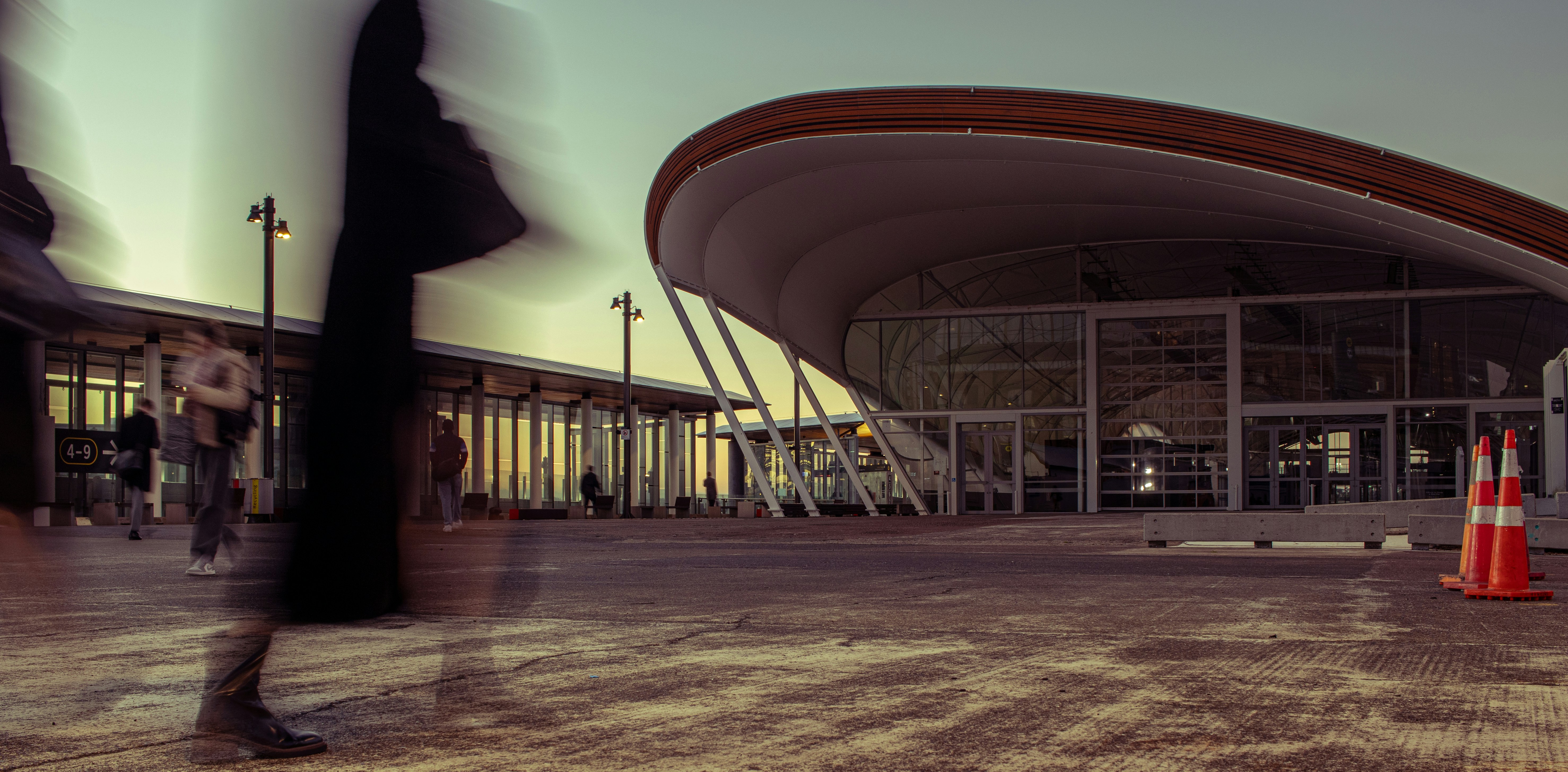 Motion at the Modern Atrium: Harried Passersby Near the Curved Glass Canopy