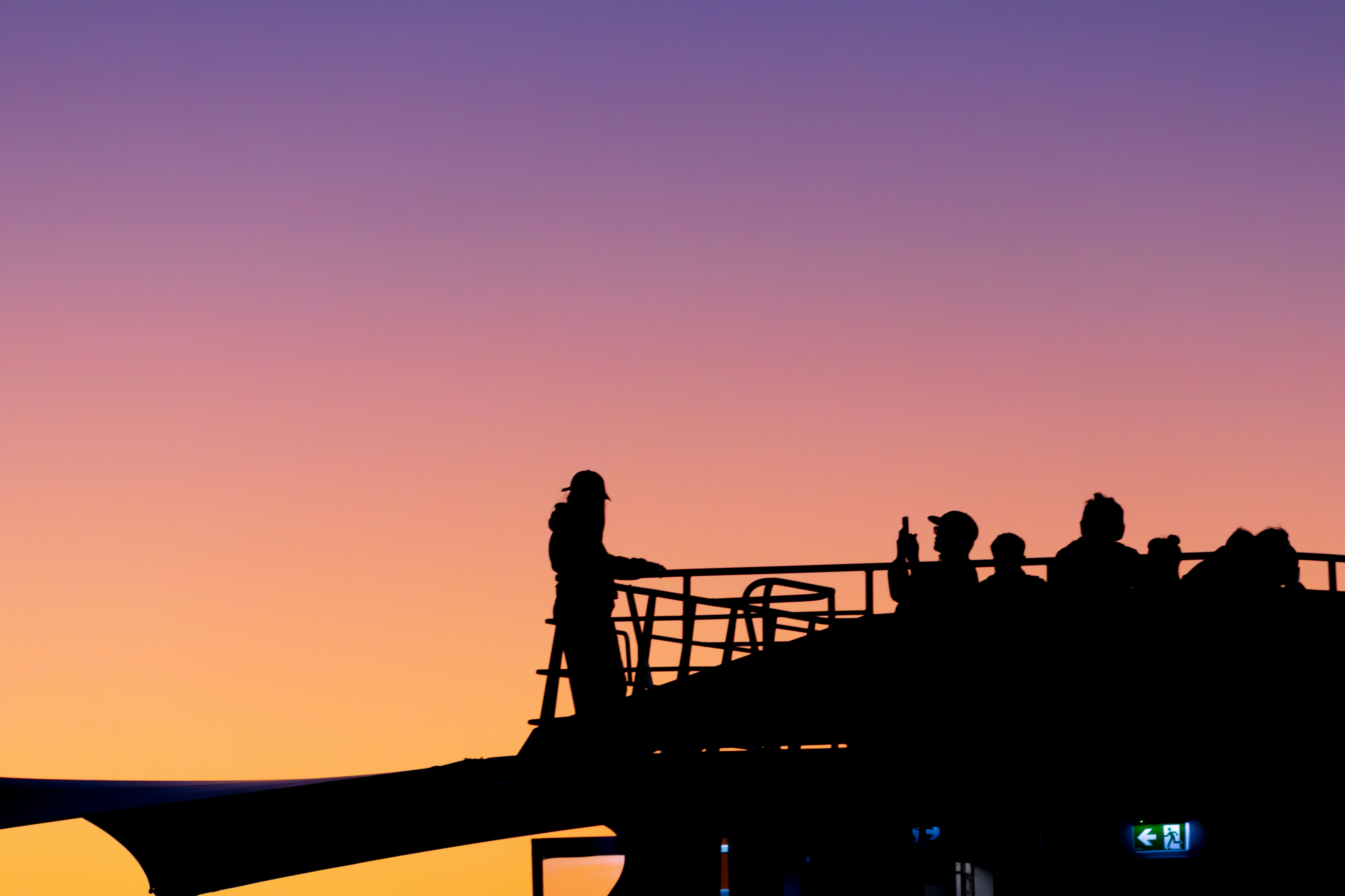 Silhouette at Sunset: Figures on a Distant Pier
