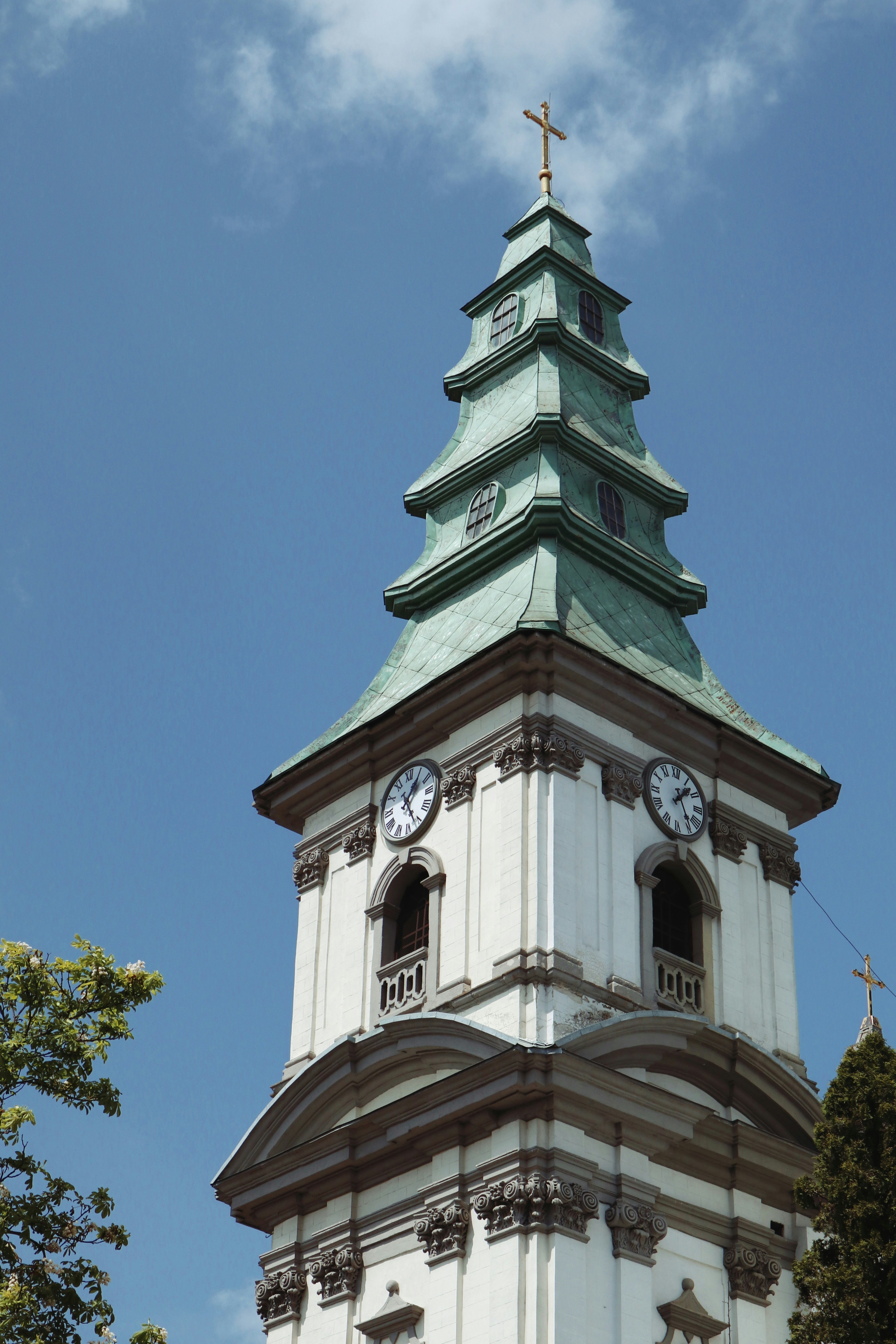 Clocktower Crowned in a Verdigris Spire Reaches Toward a Clear Sky