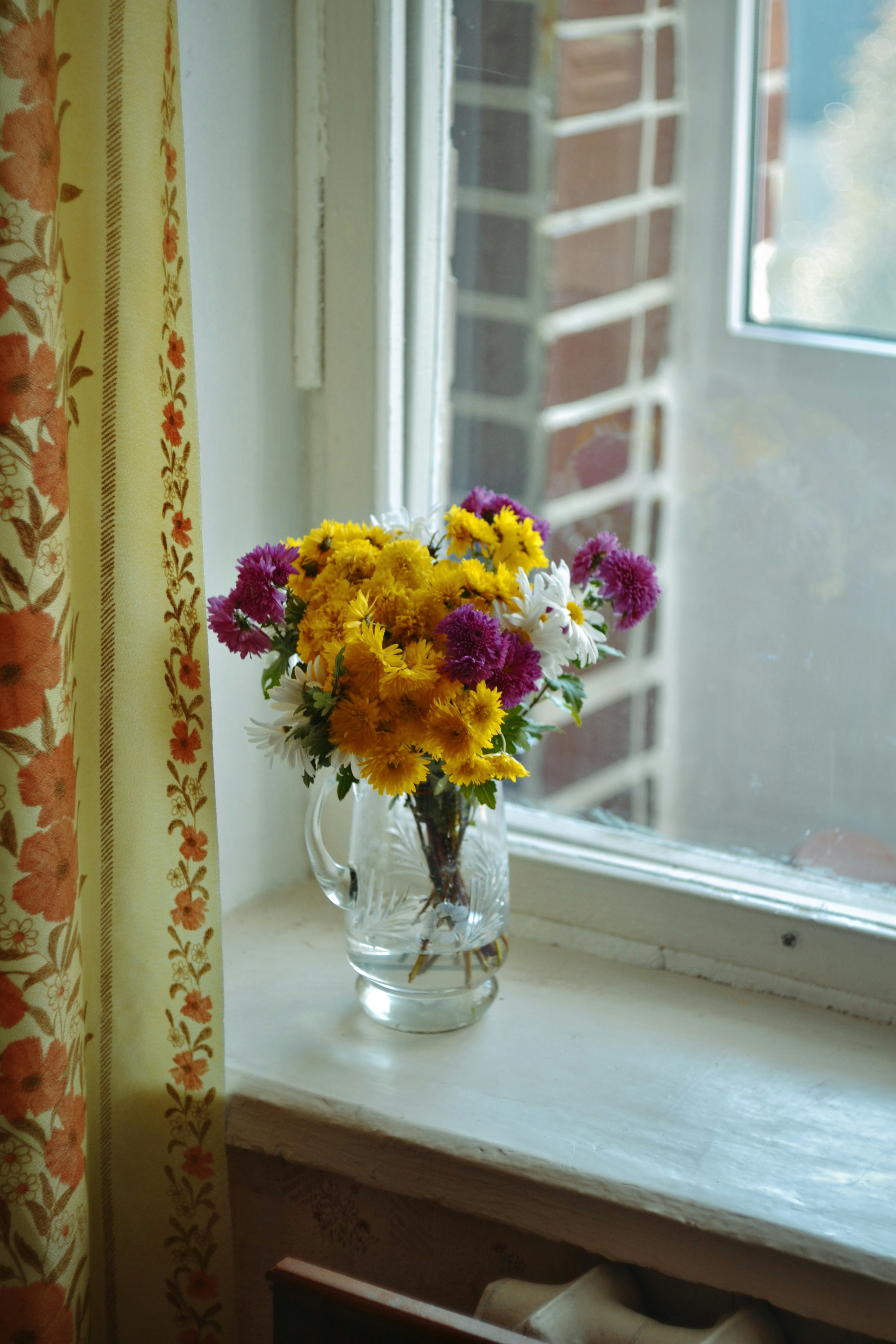 Bouquet on a Window Sill: Sunlit Glass Vase Framed by Floral Drapes