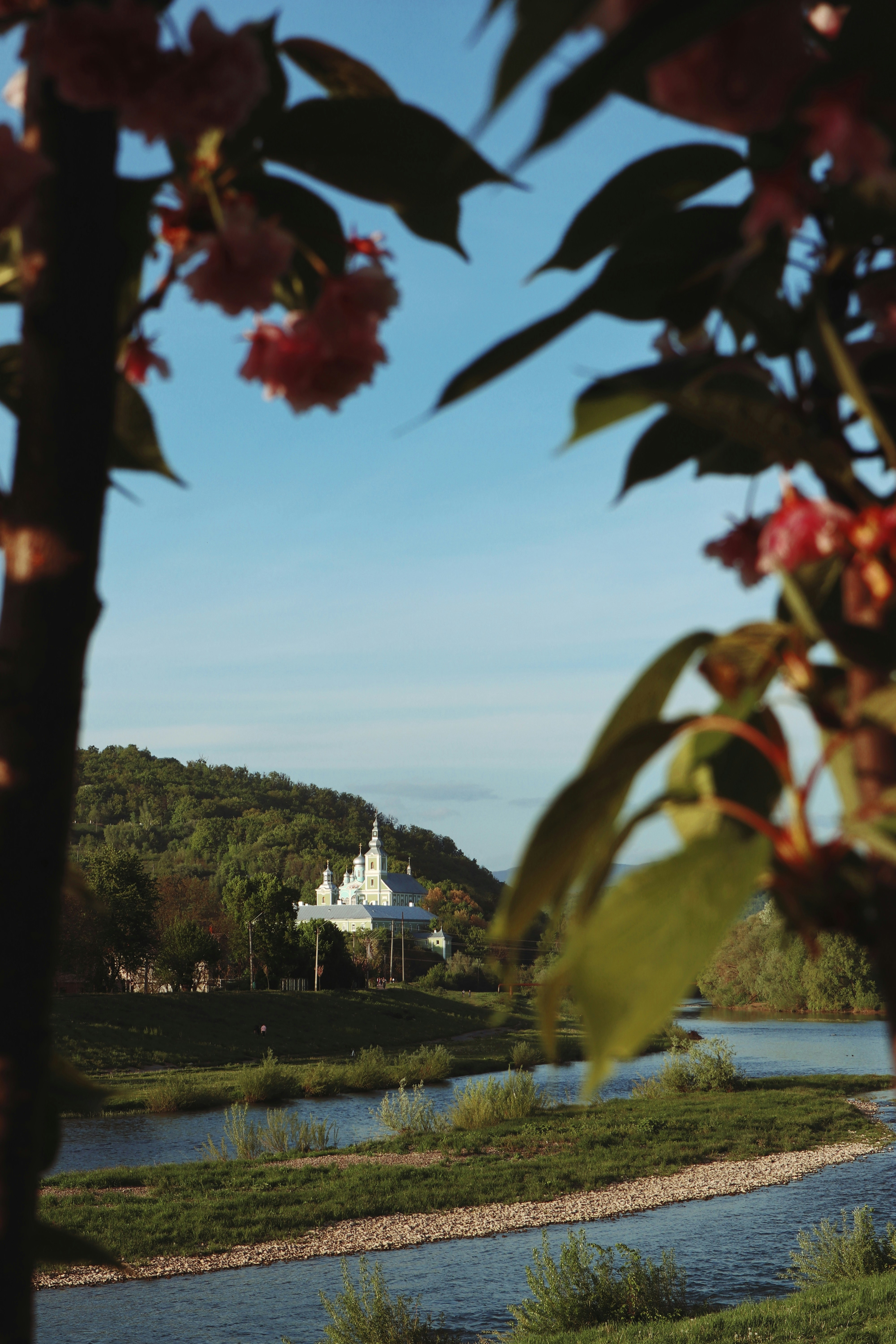 Hidden Chapel on the Riverbank Framed by Blooming Branches