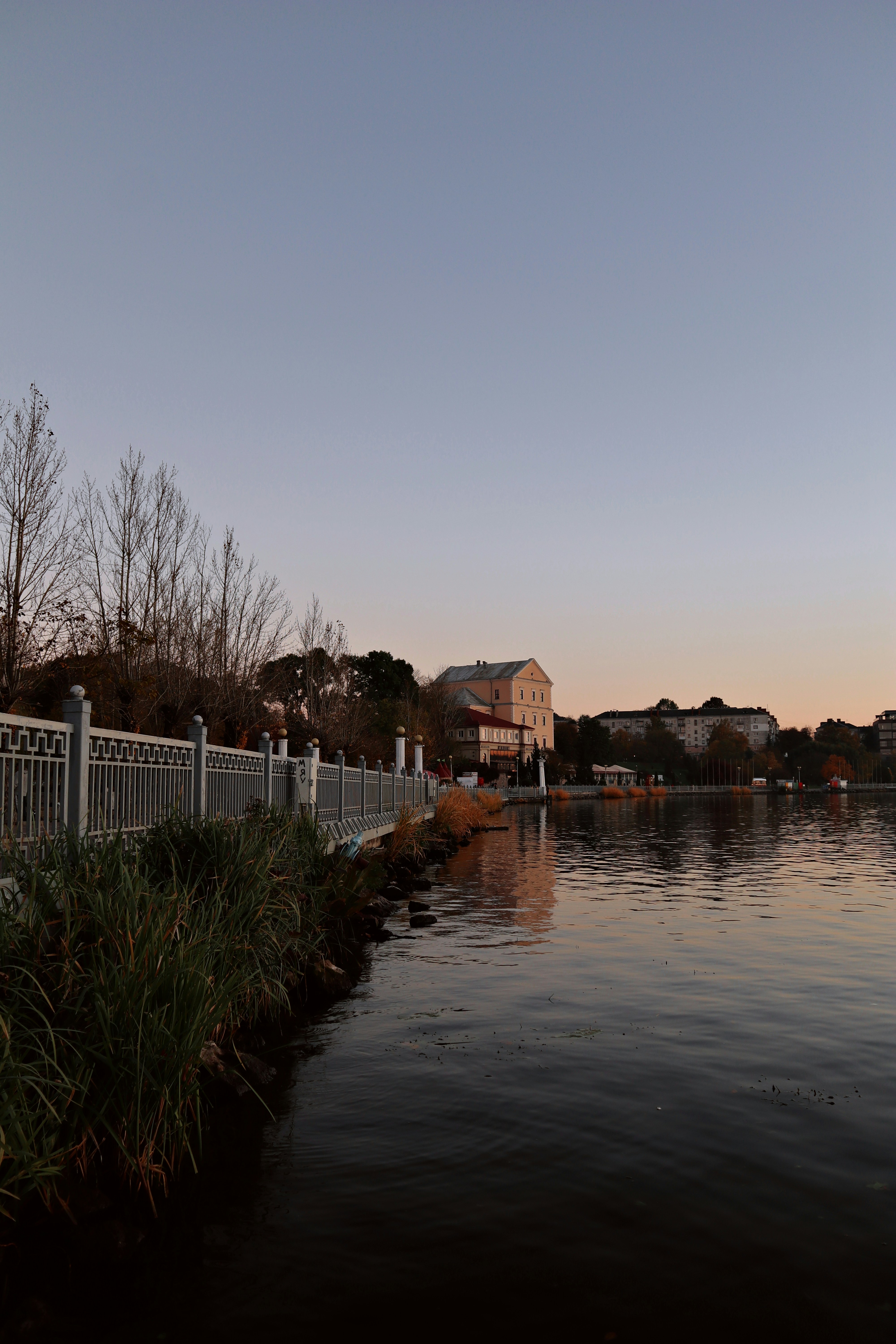  Riverside Promenade at Dusk: Calm Water and White Railings