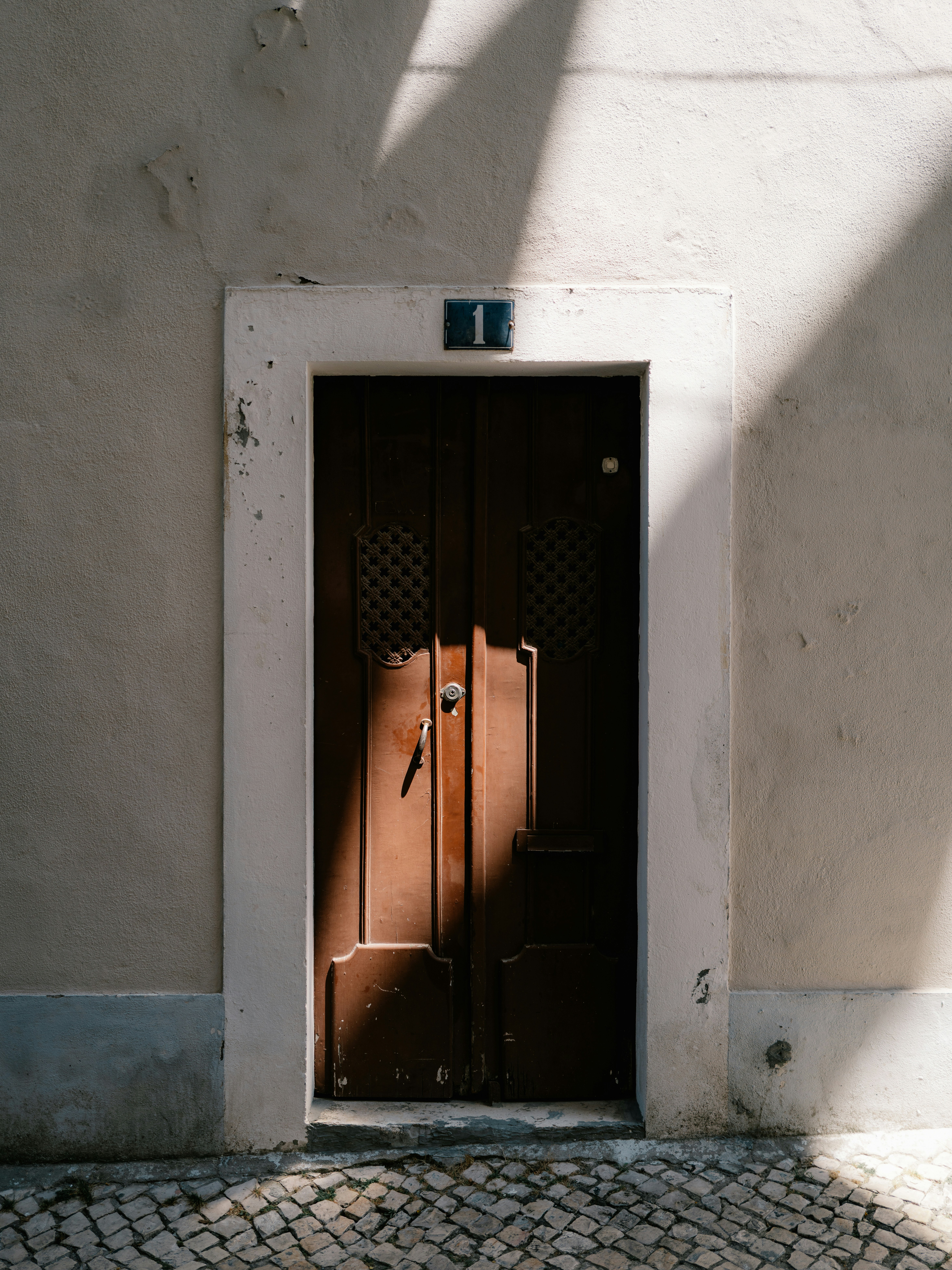 Doorway in shadowed Facade: A Quiet Passage Amid Sunlit Slab