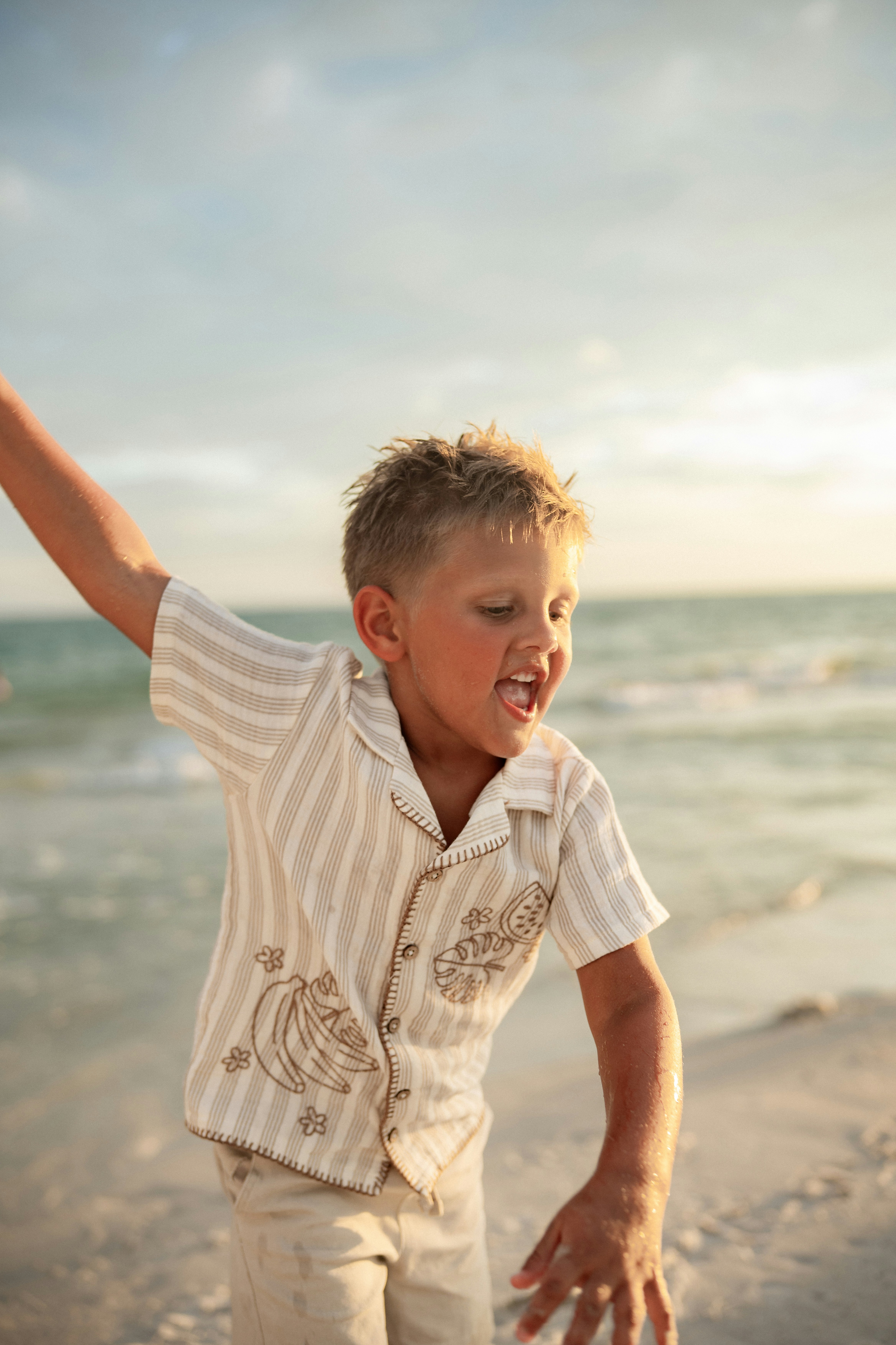 Joyful Beach Moment: Child in Motion with Ocean Backdrop