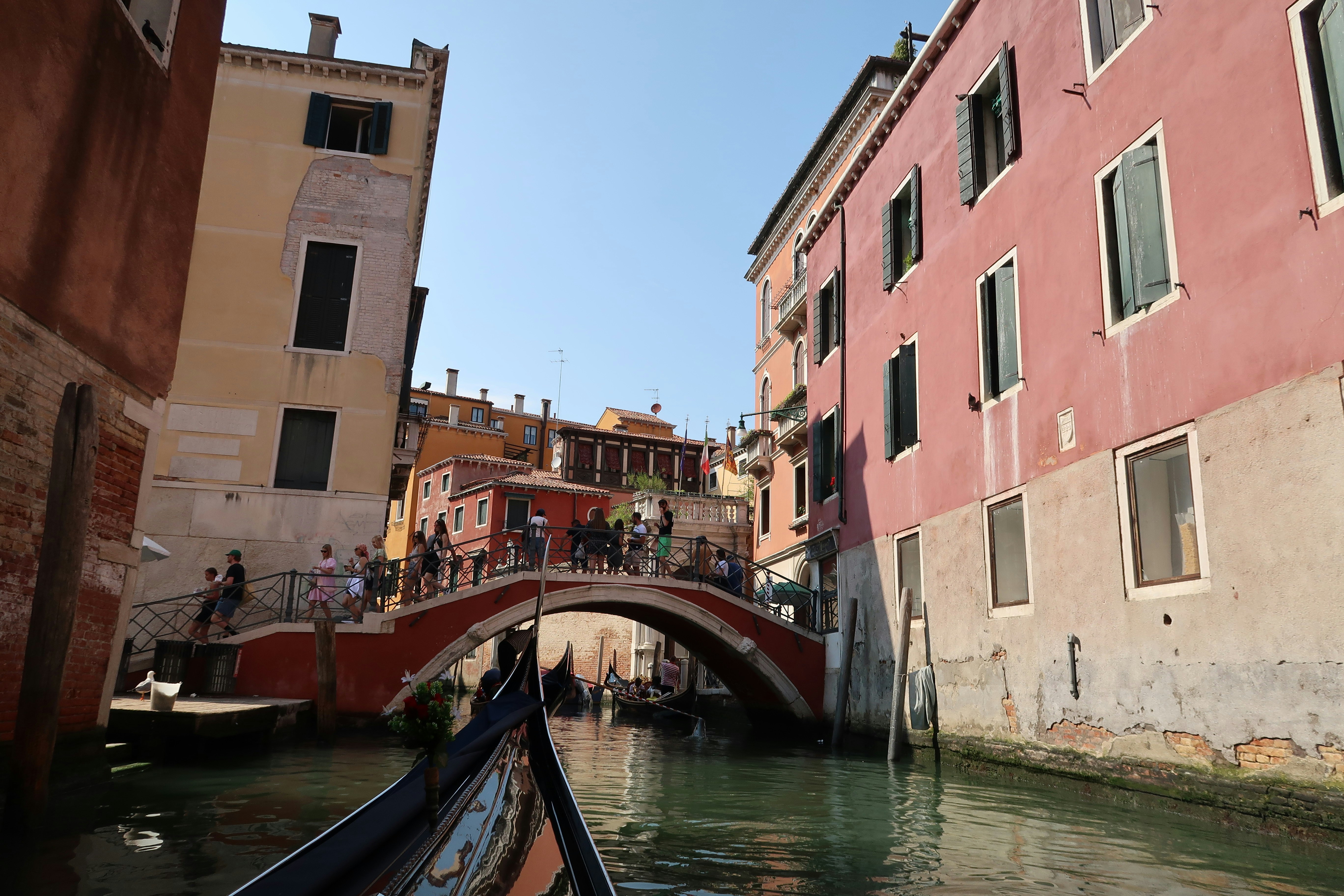 Gondola Glide Under a Brick Arch in a Lively Venetian Canal