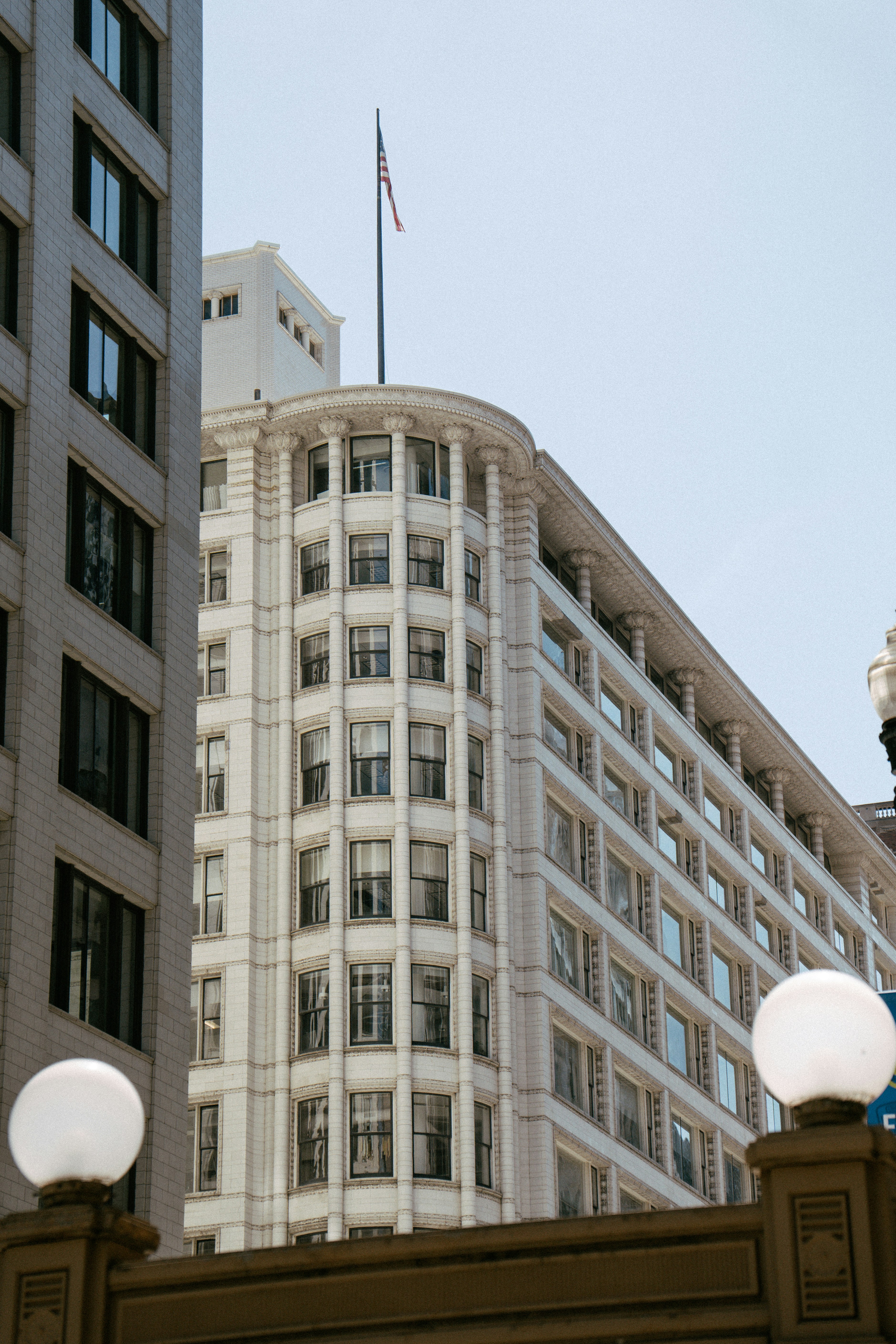 Flag atop curved courthouse-like facade under a pale blue sky