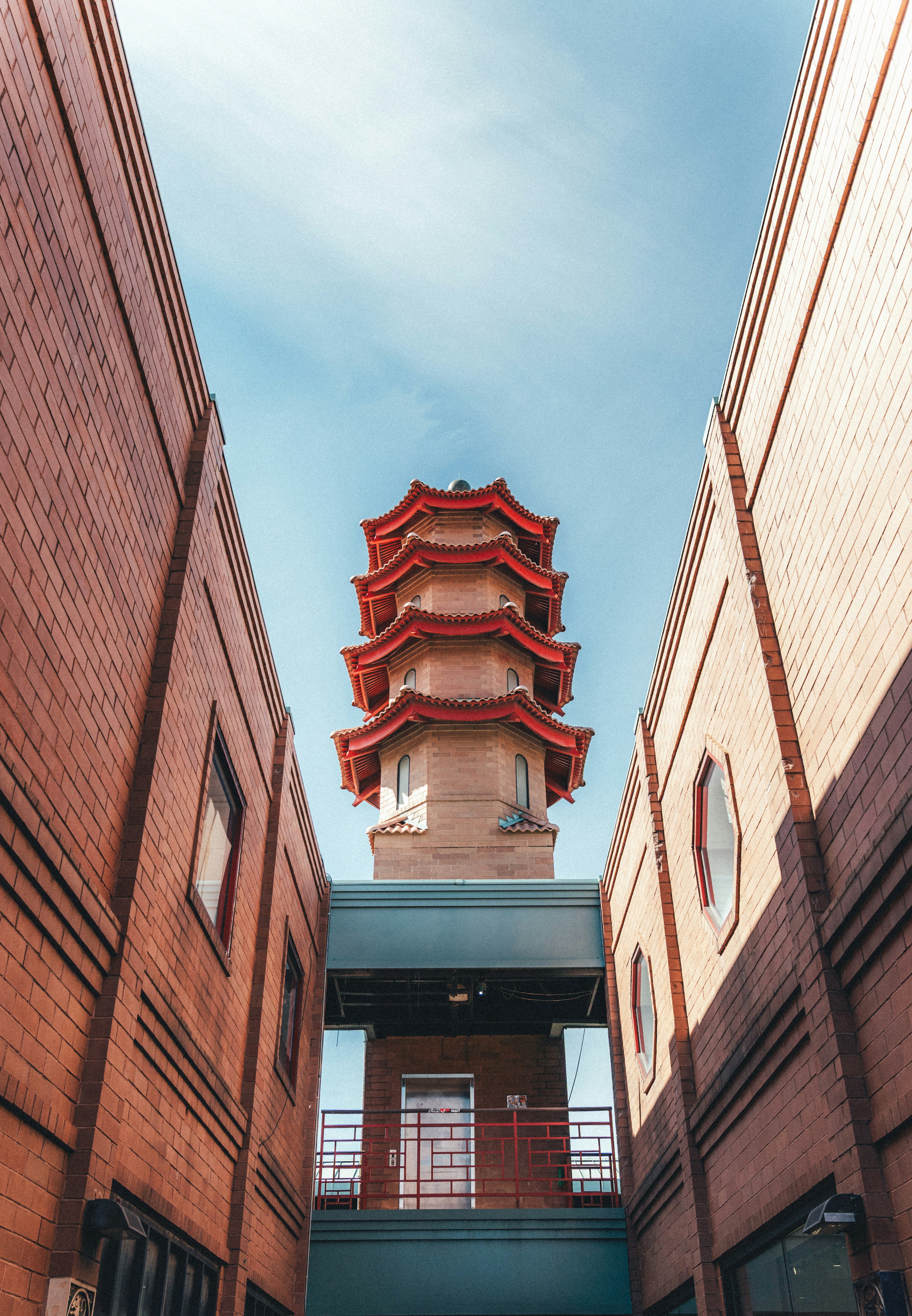 Upward Gaze: A Red Pagoda Rising Between Urban Red Bricks