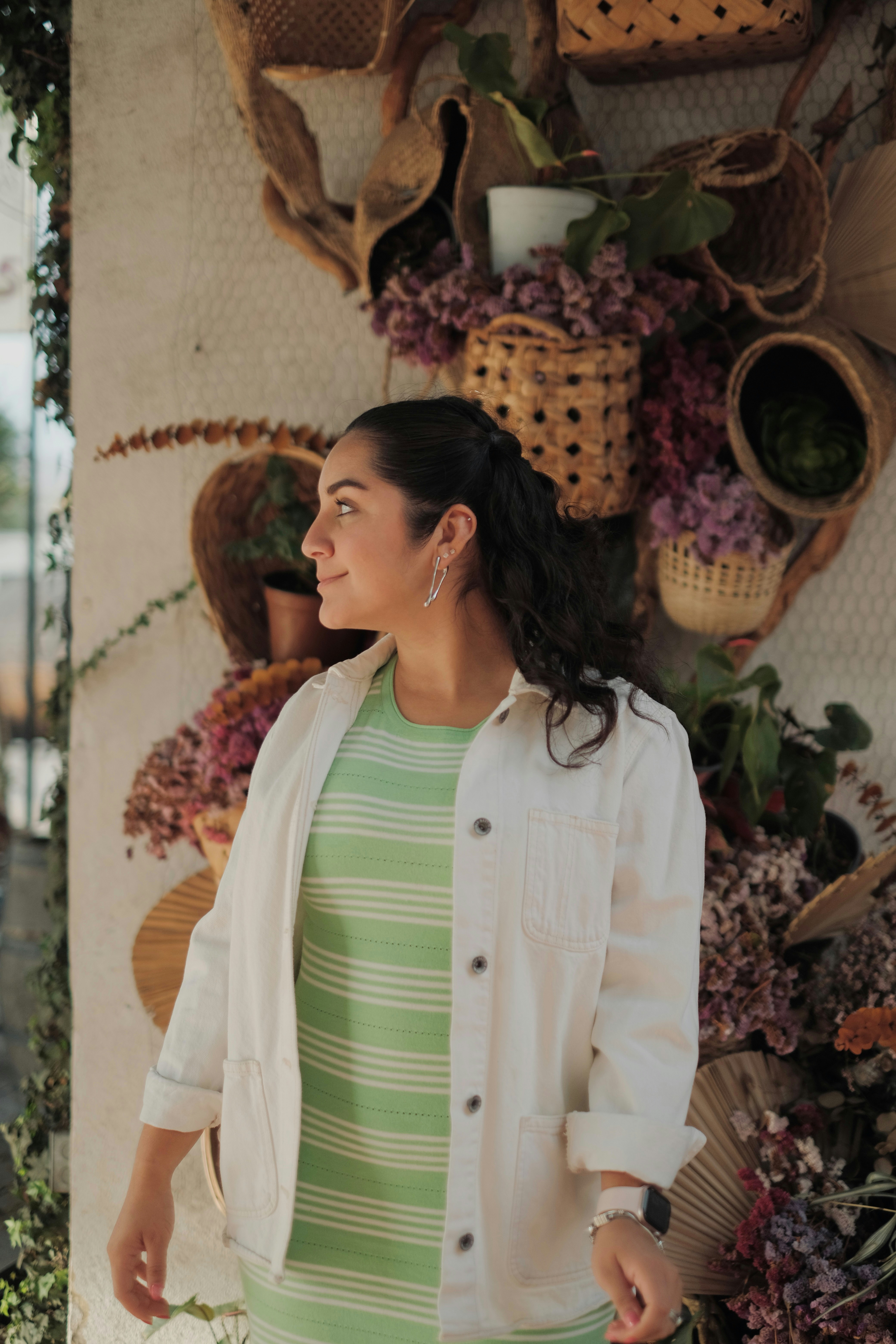 Portrait in Bloom: A Woman in a White Jacket Among Floral Baskets
