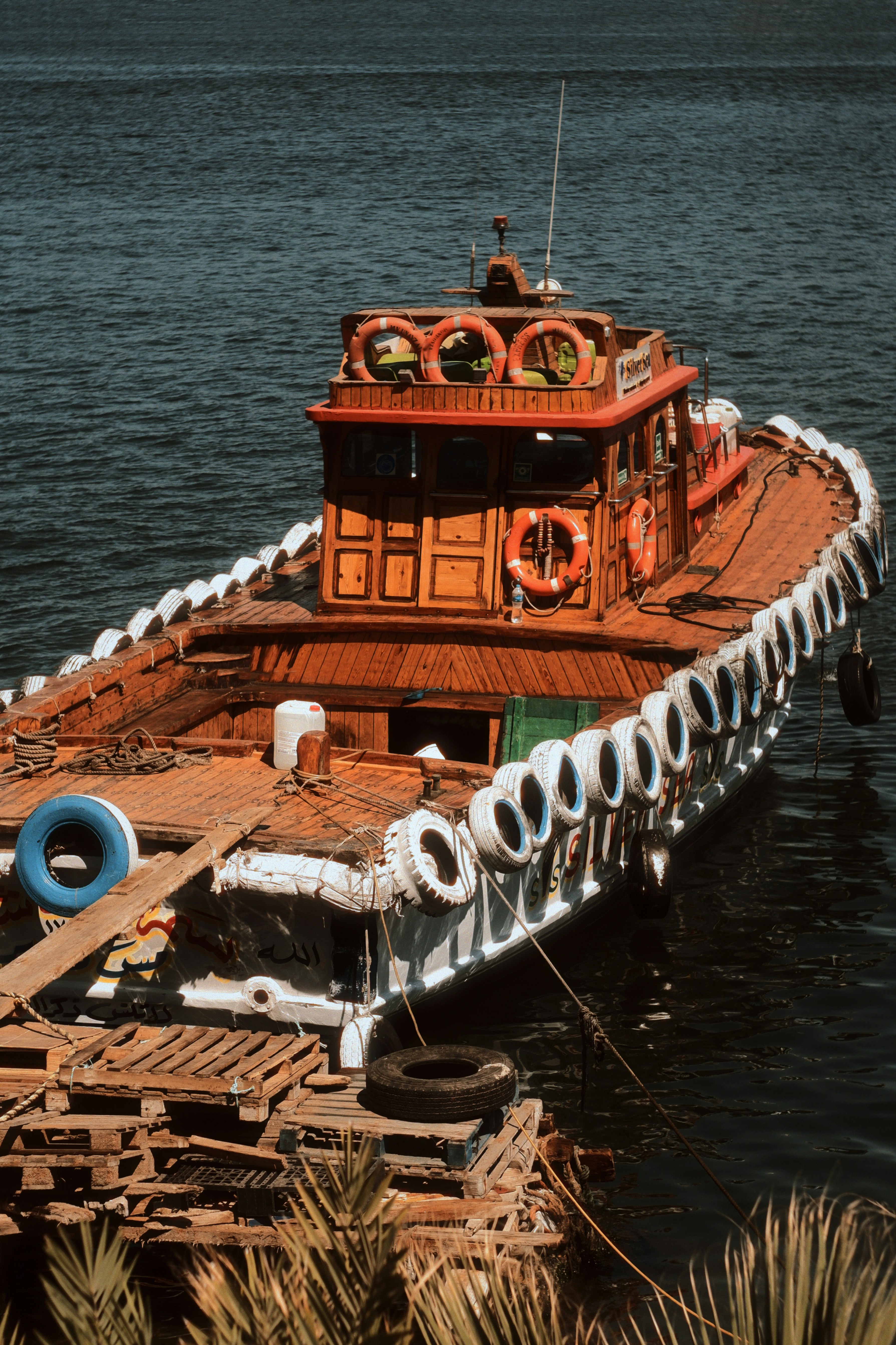Orange Trawler: Sunlit Deck and Treasured Lifebuoys along a Quiet Port