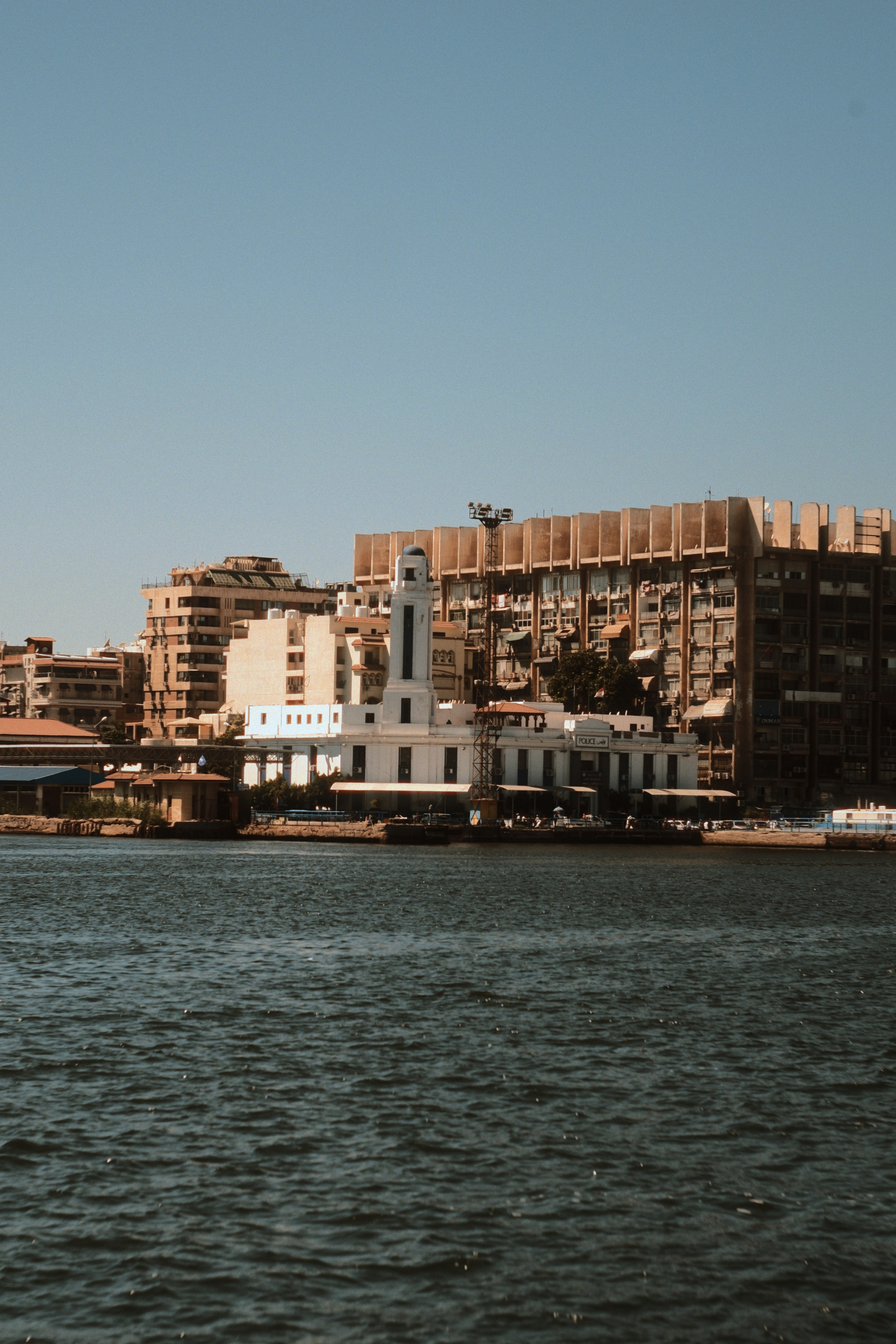 White Lighthouse Emblem Against a Harbor Cityscape